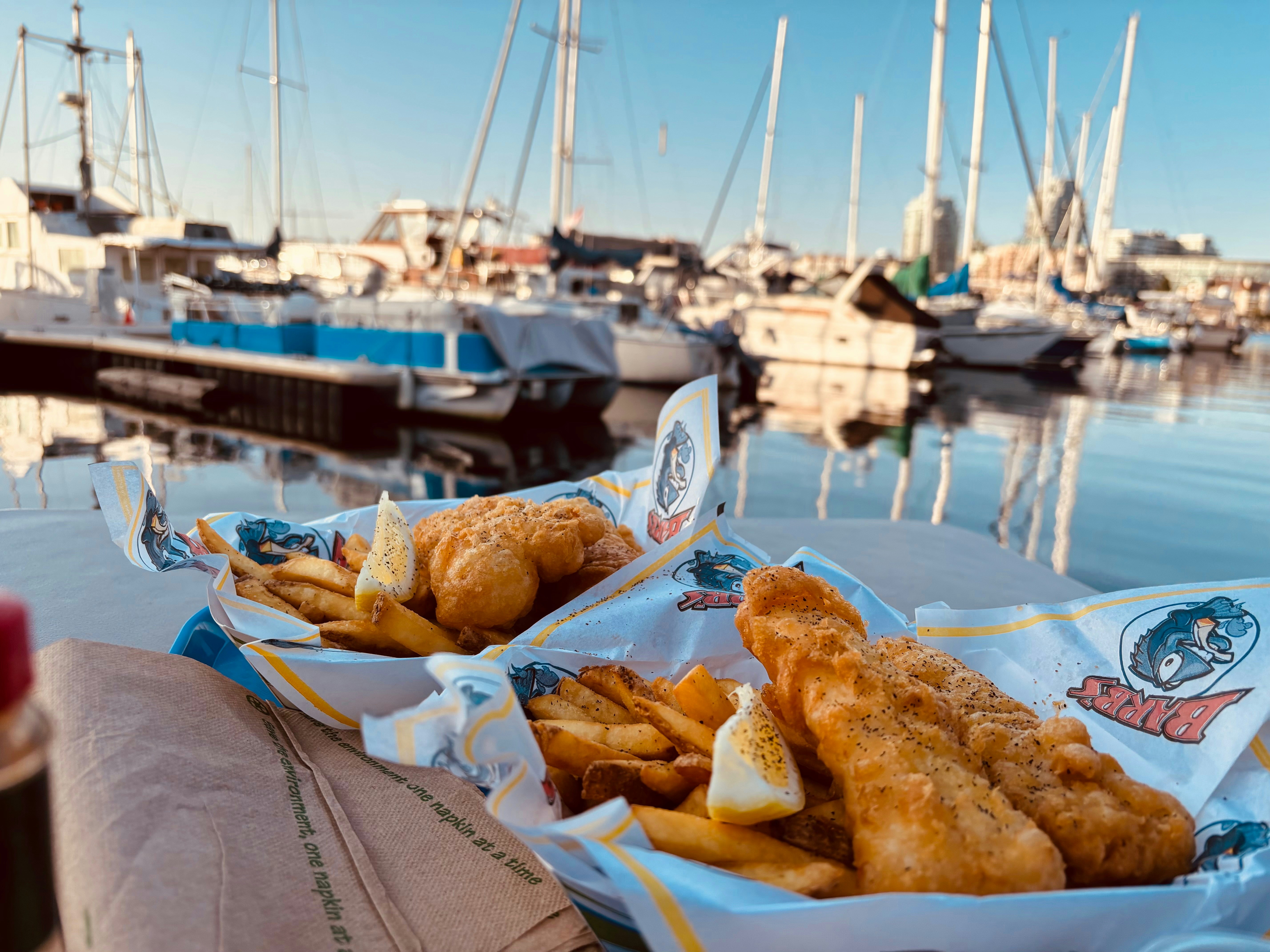 Marina Fry Feast: Golden fish and chips framed by calm blue water and sails