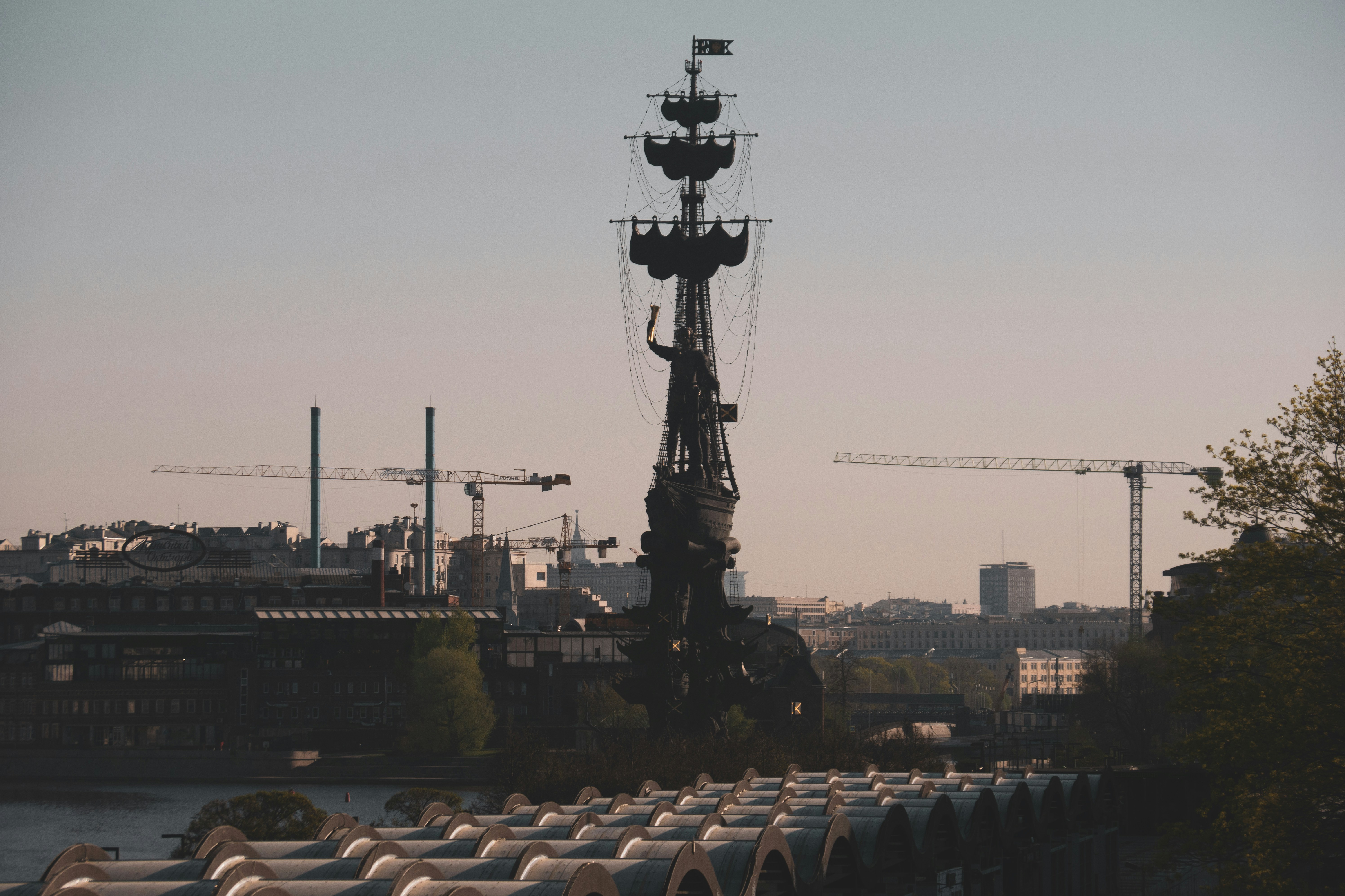 Harbor of Giants: A Sunset Silhouette of a Maritime Mast against the City