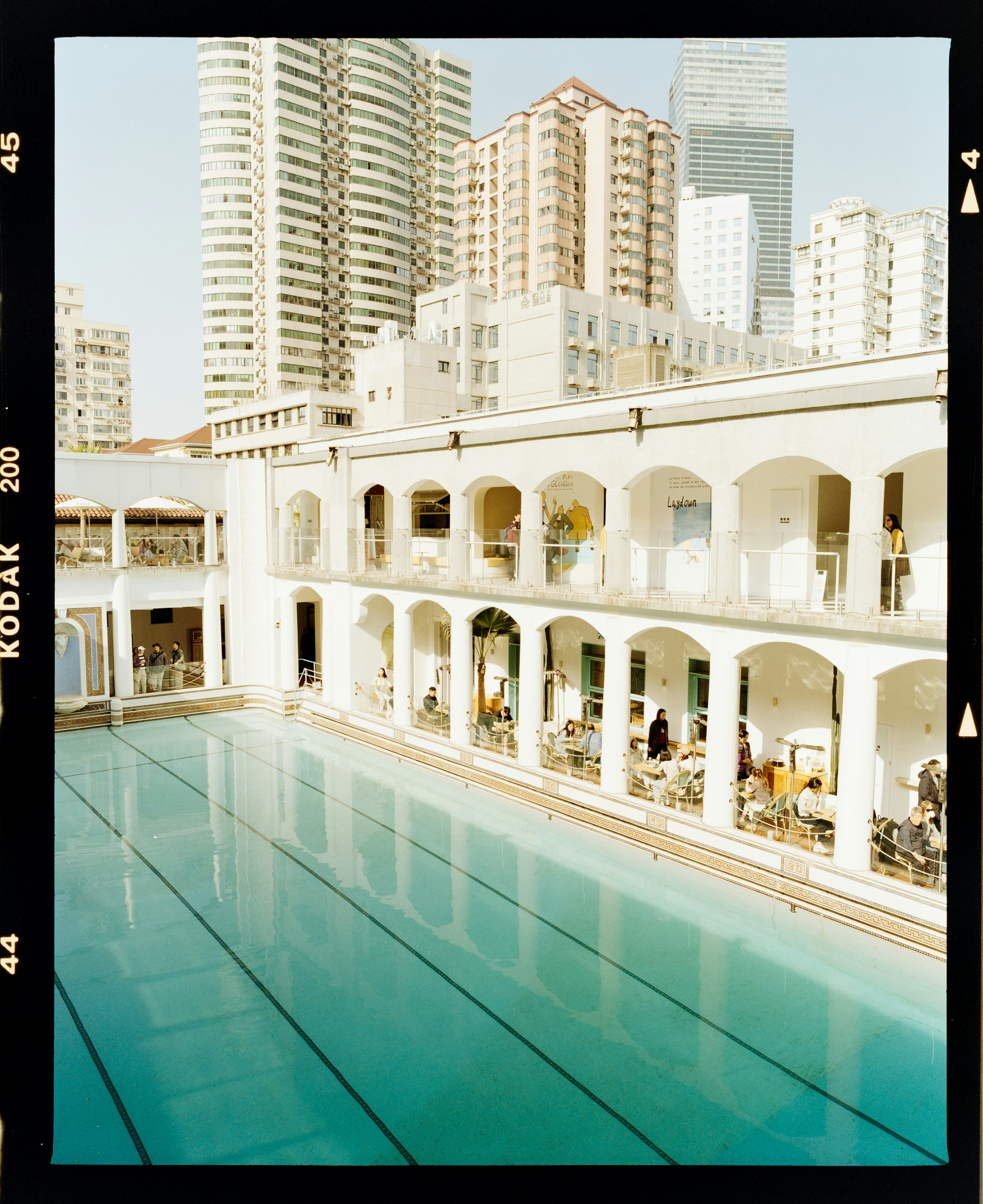 A tranquil swimming pool surrounded by elegant architecture and bustling city life, showcasing a blend of leisure and urban energy.