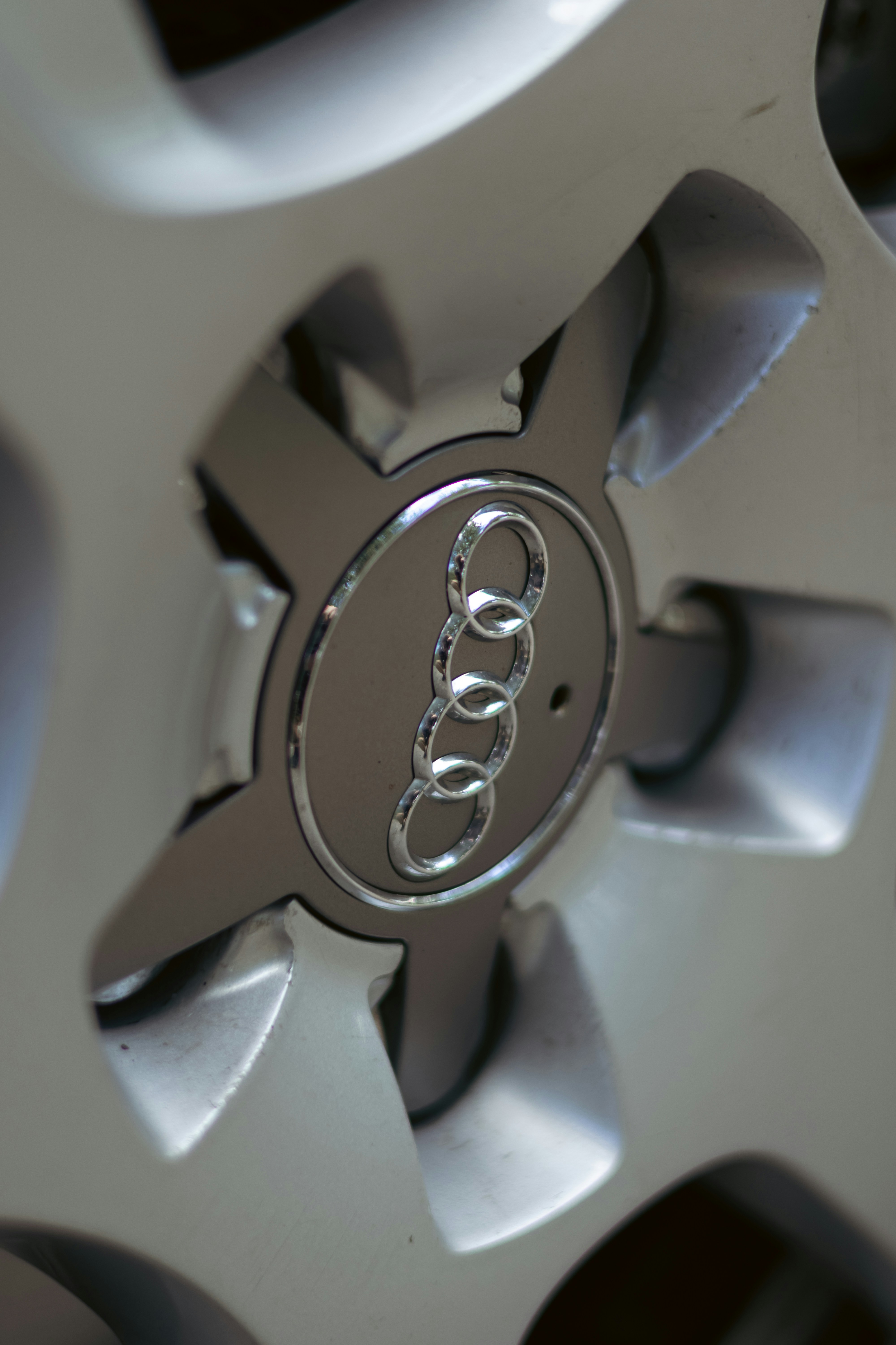Tight Macro: The Audi four-ring emblem nestled in a silver alloy wheel