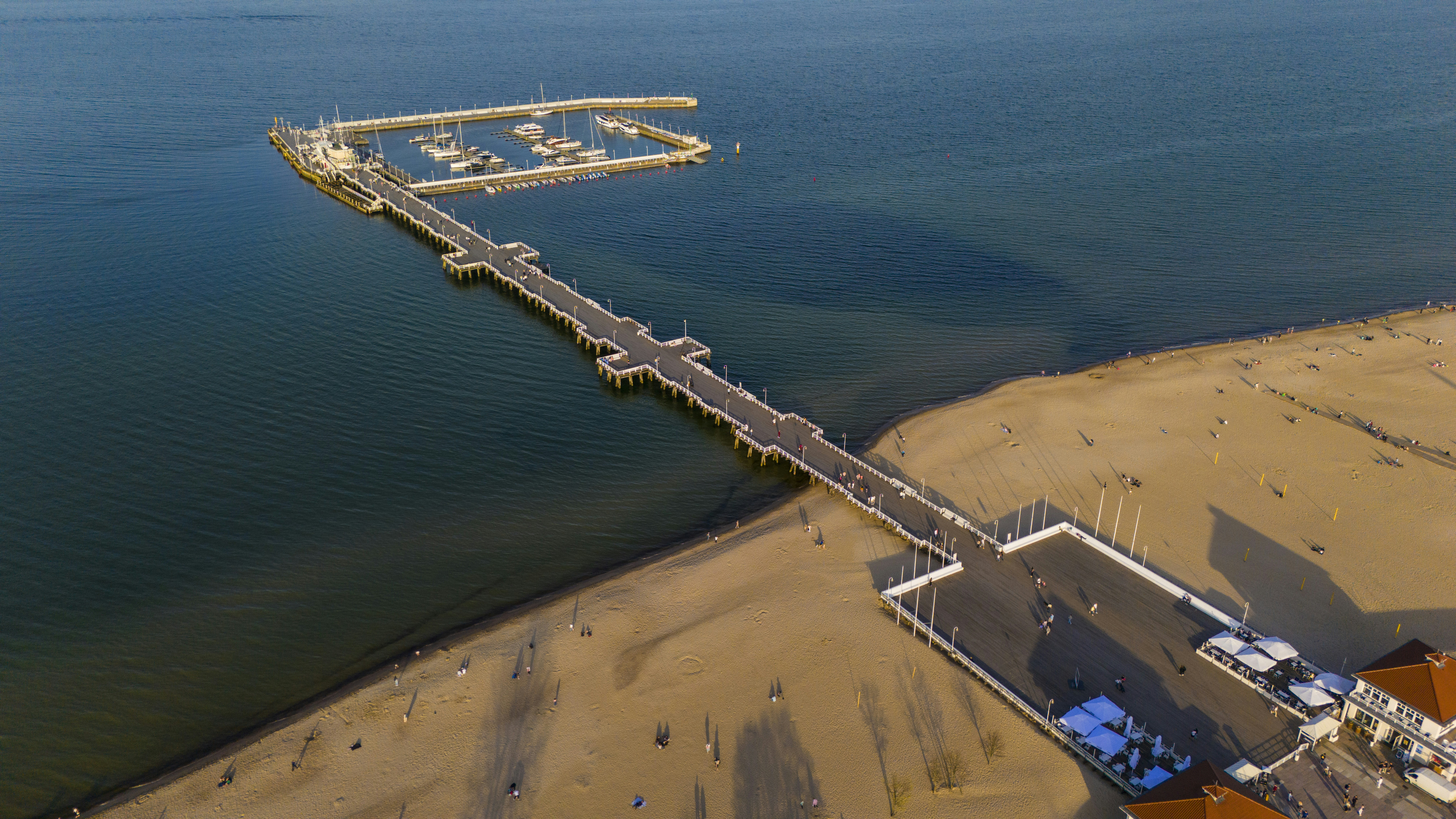 Tideward Geometry: Aerial View of a Pier Reaching the Sea