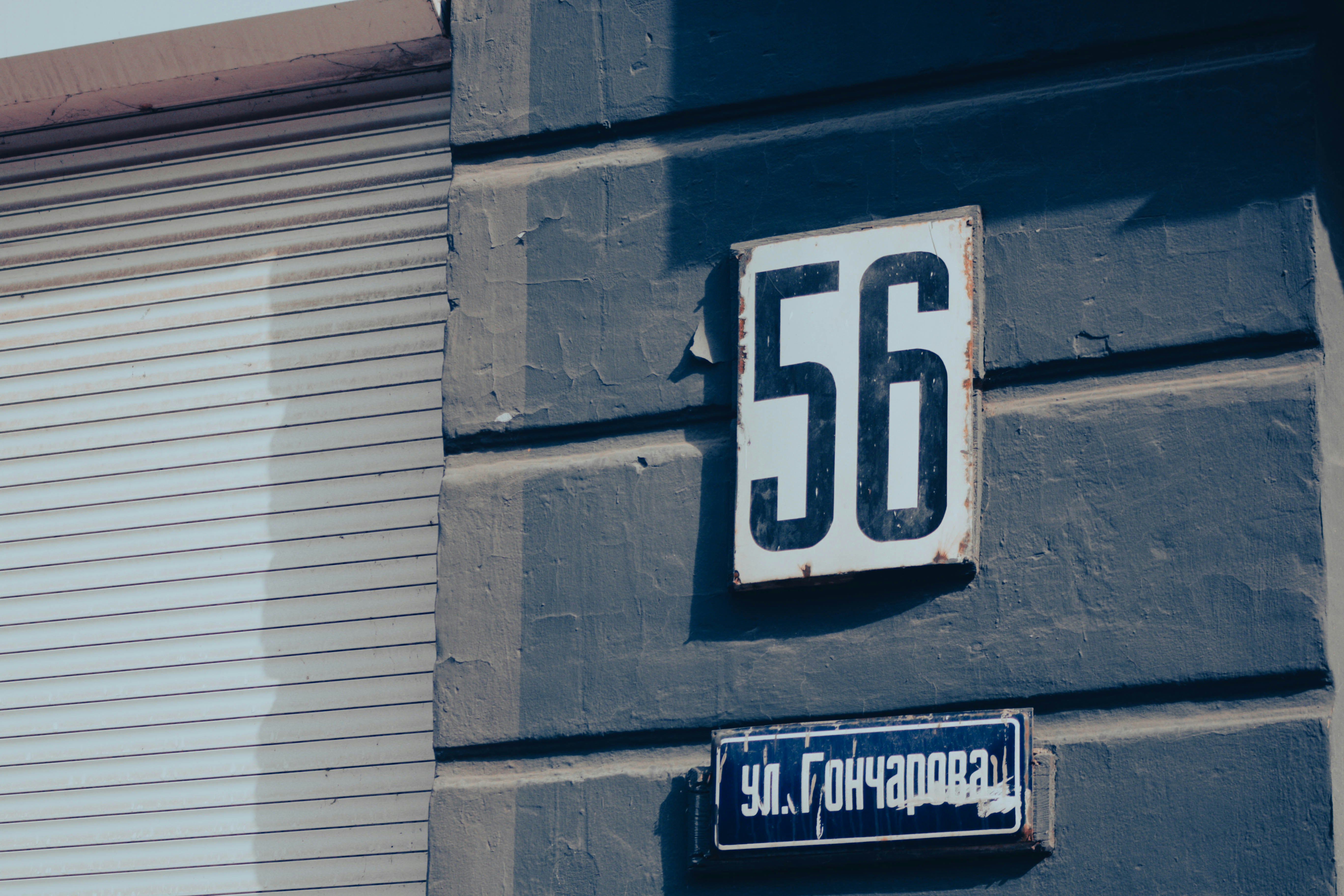 Weathered building number 56 on a city street, showcasing a vintage style. The adjacent street sign adds context to the urban landscape.