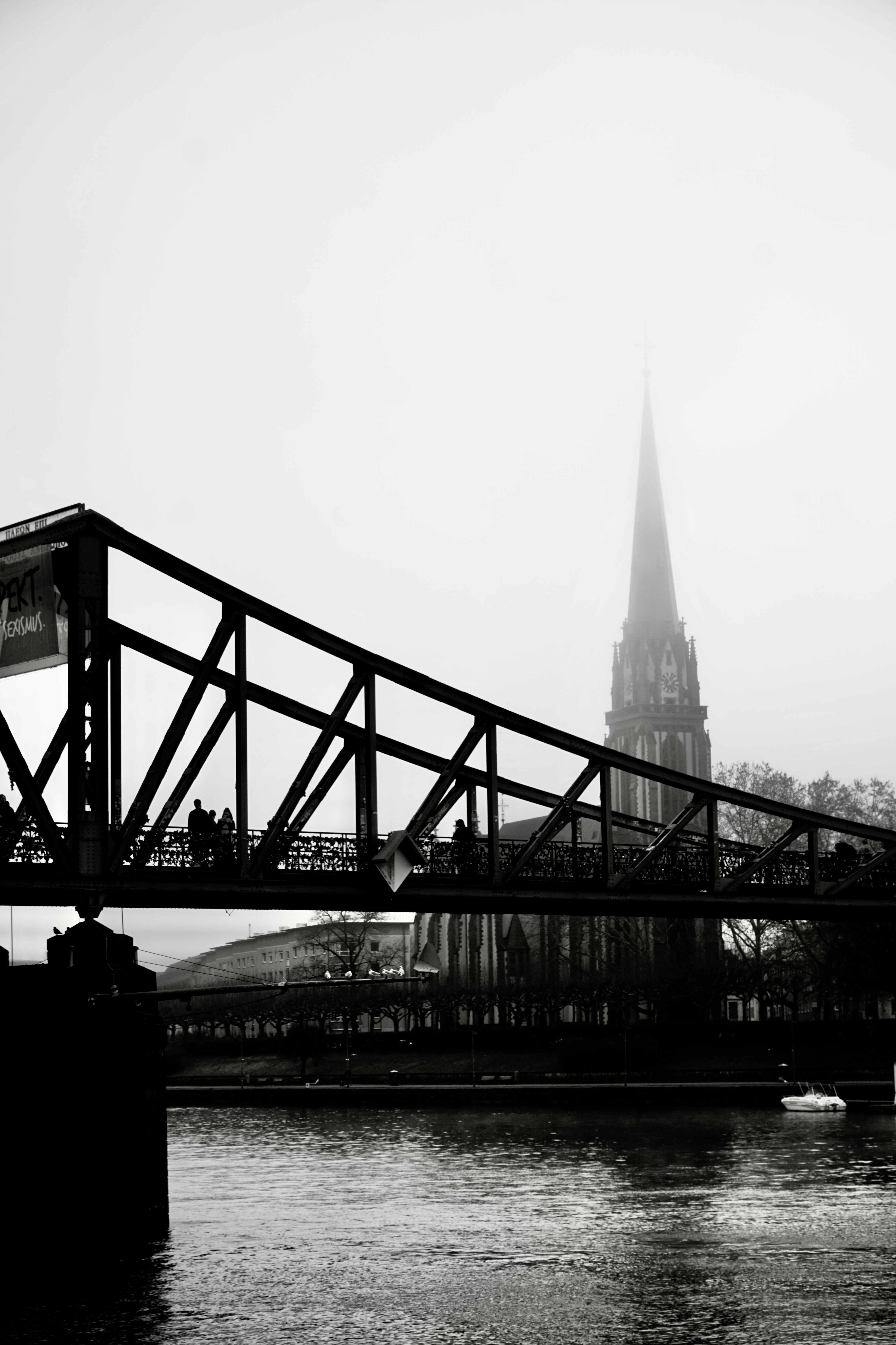 Spire in the Mist: A Silent River Crossing Beneath a Steel Bridge