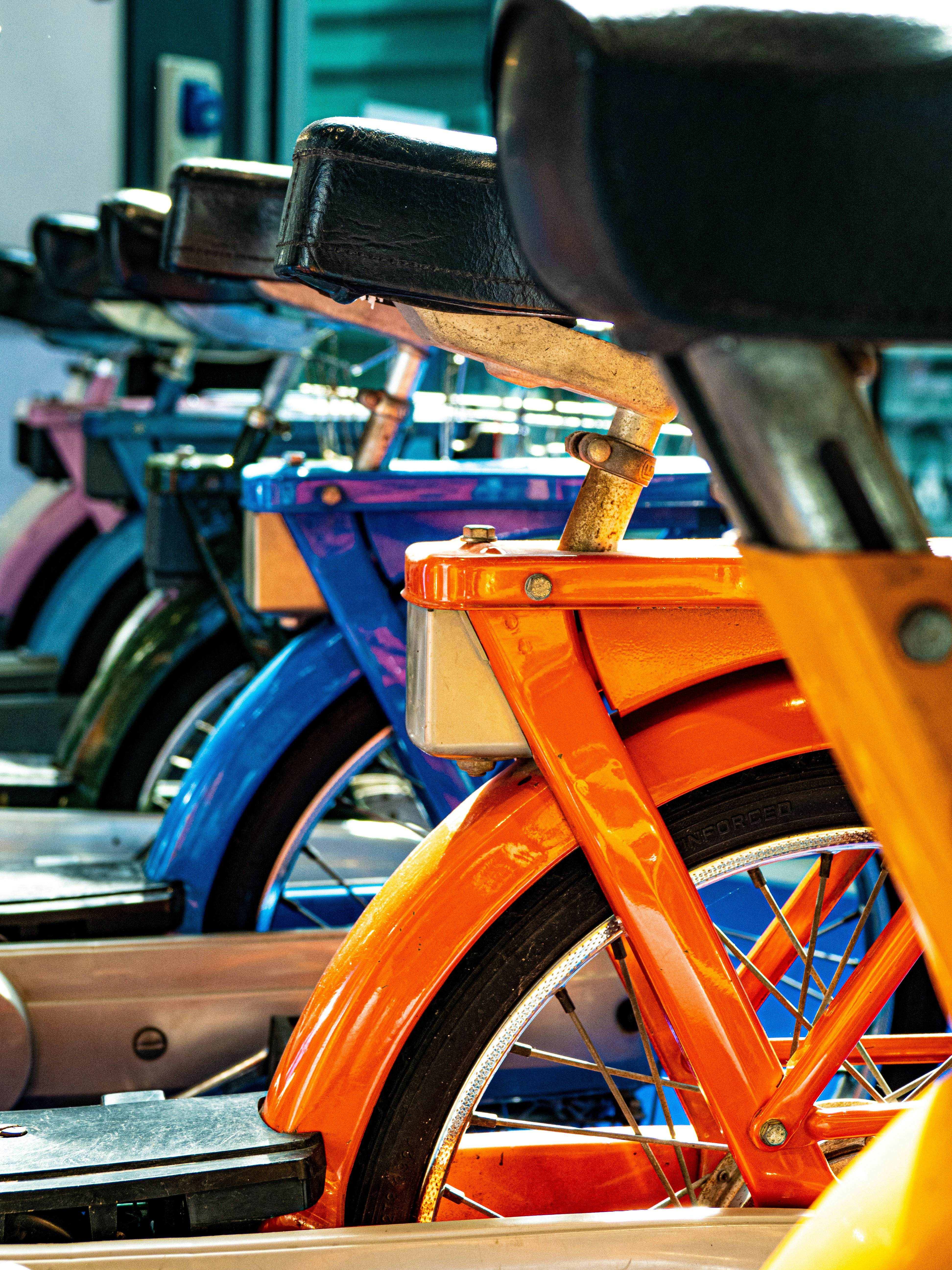 Chromatic Lineup: An Orange Foreground Leads a Row of Colorful Bicycles