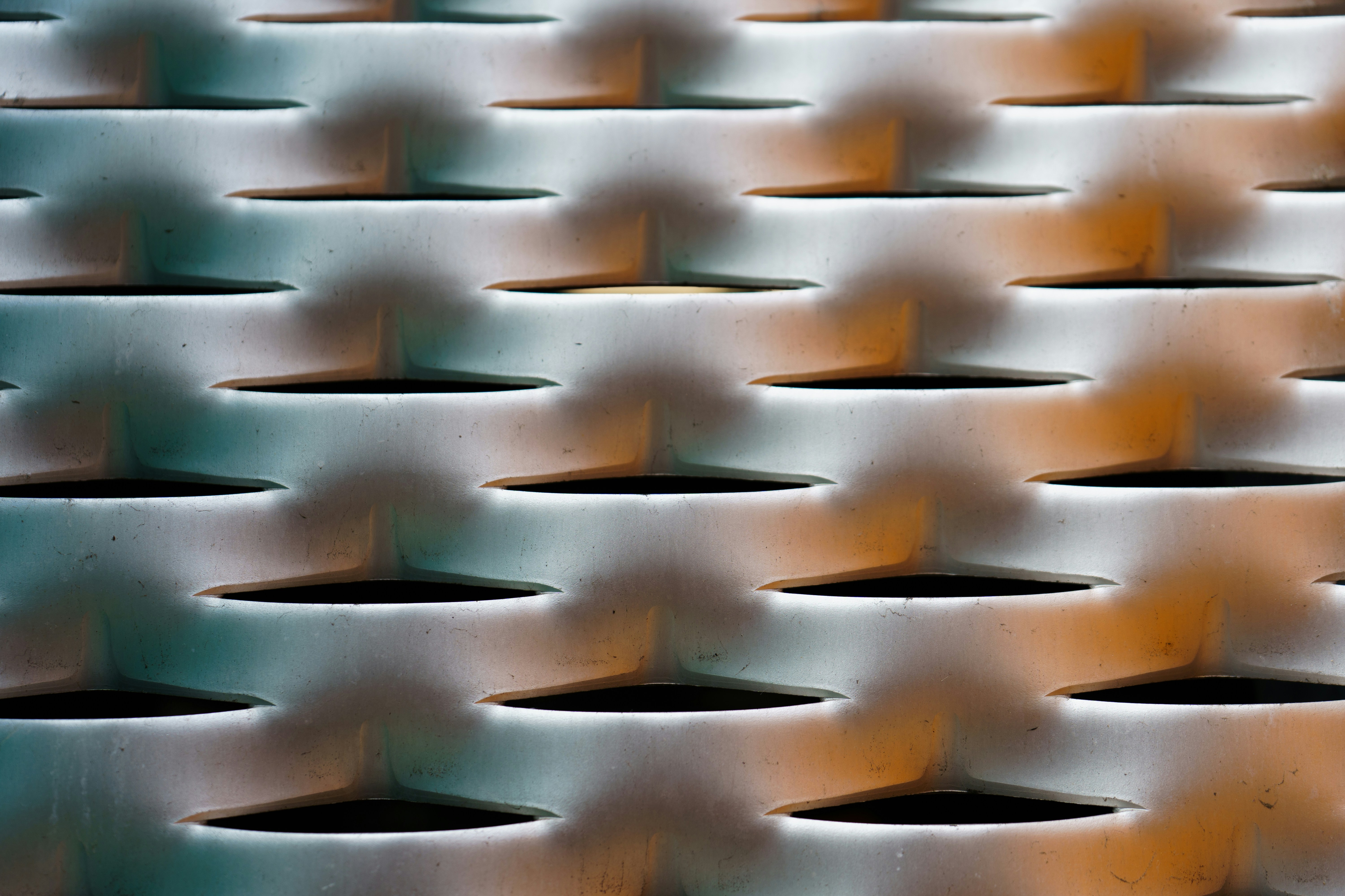 Abstract pattern of perforated material showcasing a blend of light and shadow. The design creates a rhythmic visual flow.