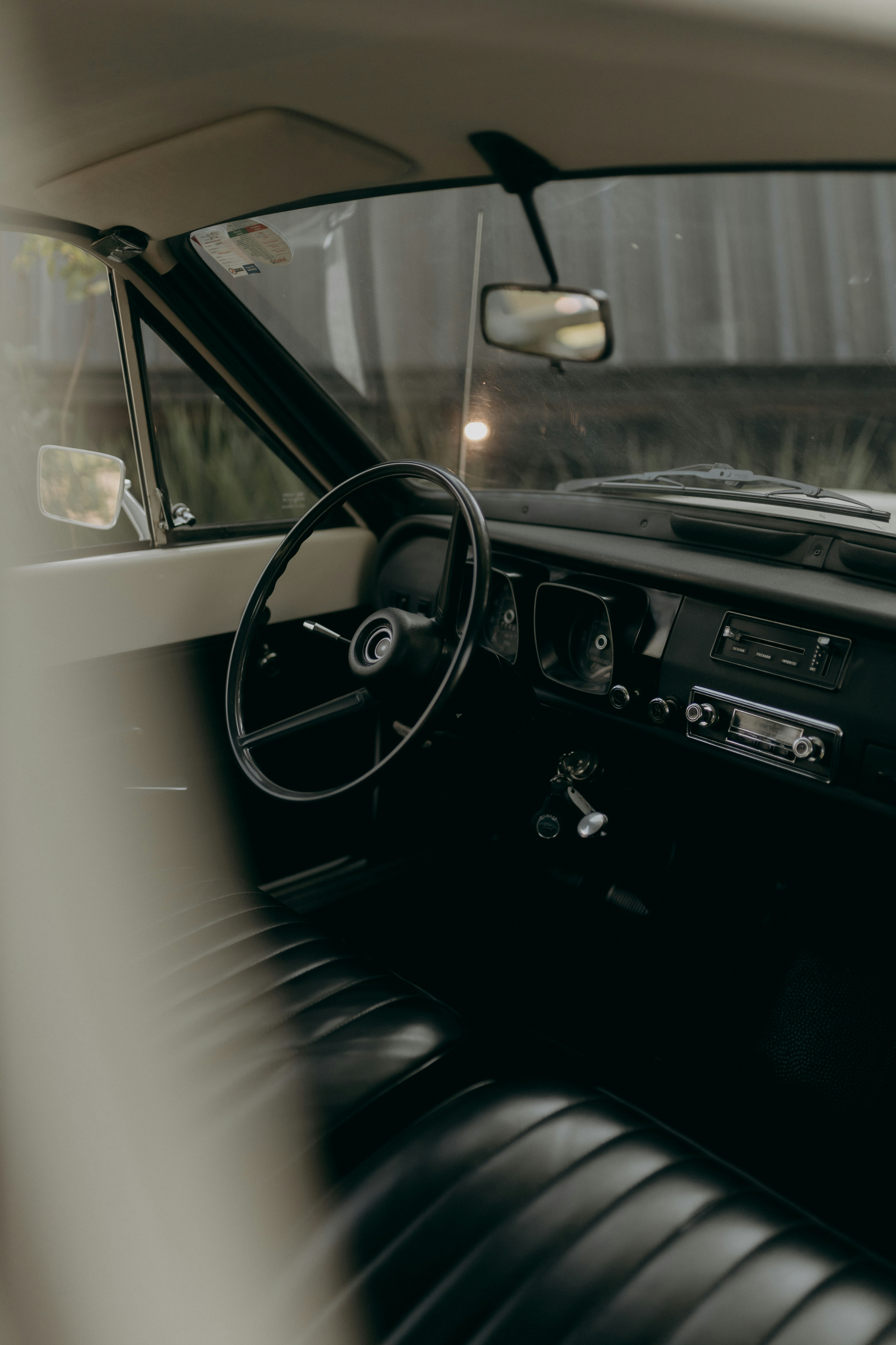 Interior of a vintage car showcasing black leather seats and a classic steering wheel, with soft lighting enhancing the nostalgic ambiance.
