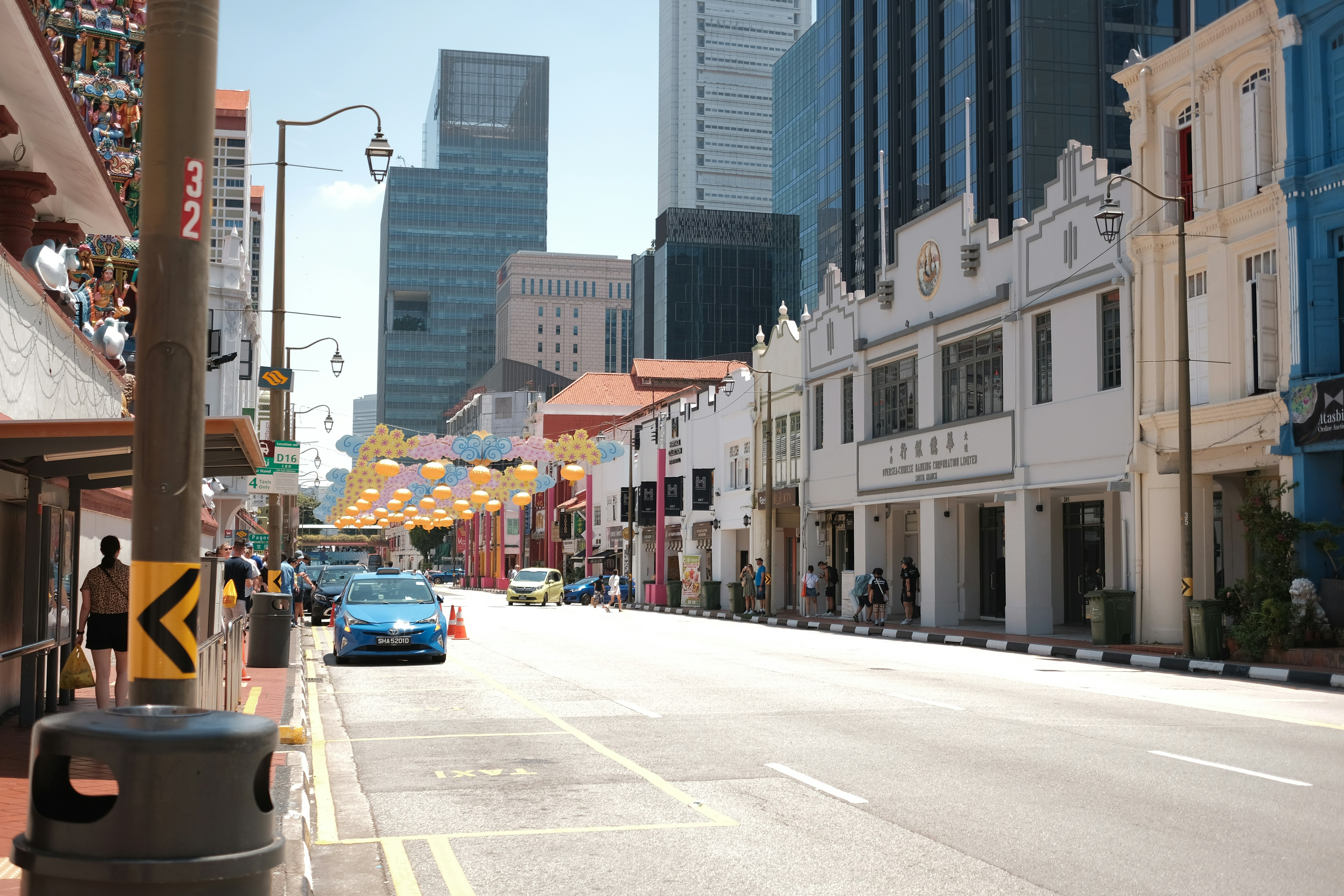 Blue Car Under Canary Umbrellas on a White-Fronted Heritage Street