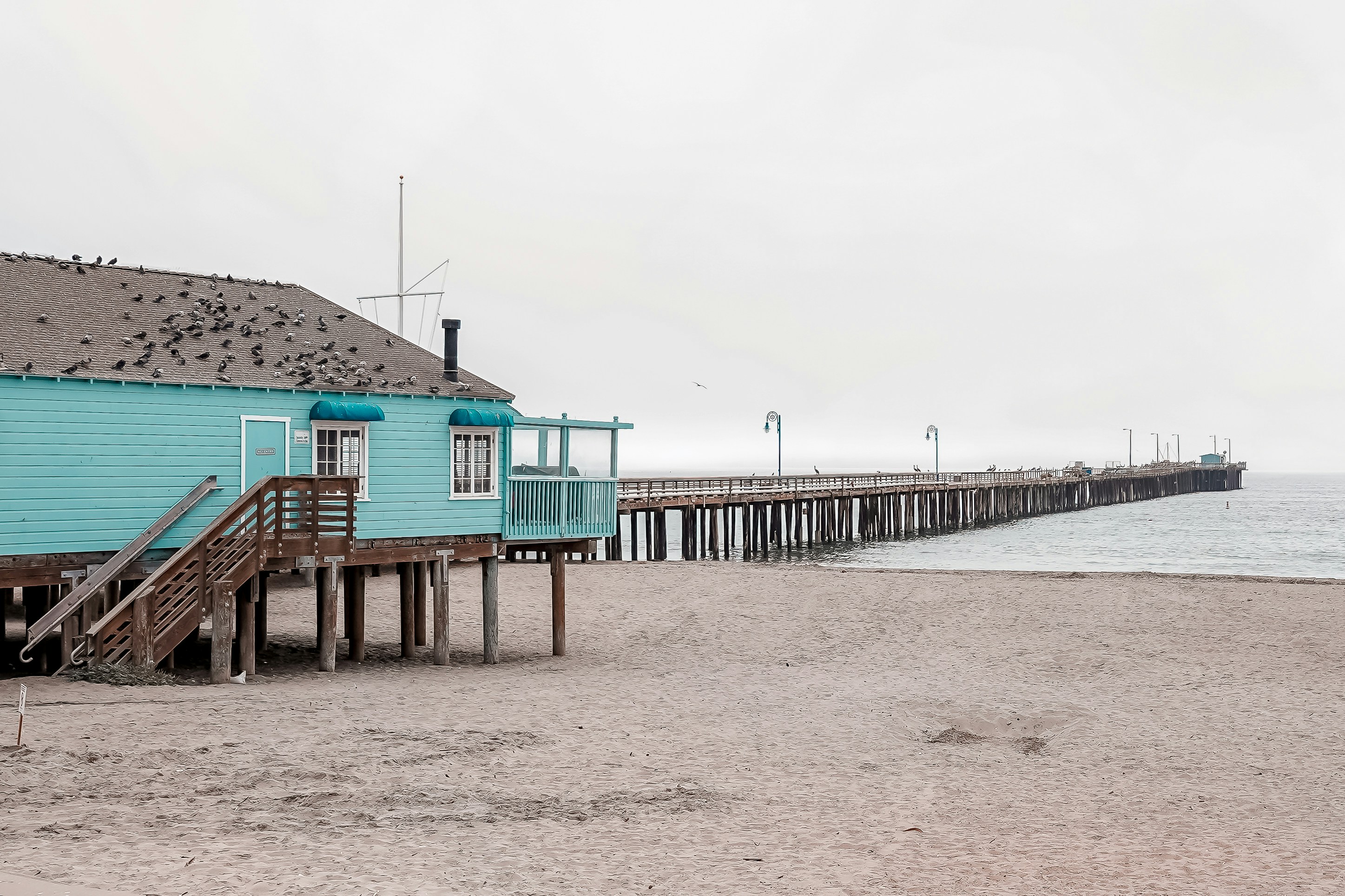 Un muelle se extiende en el océano junto a un edificio. foto – Imagen de Playa gratuita en Unsplash