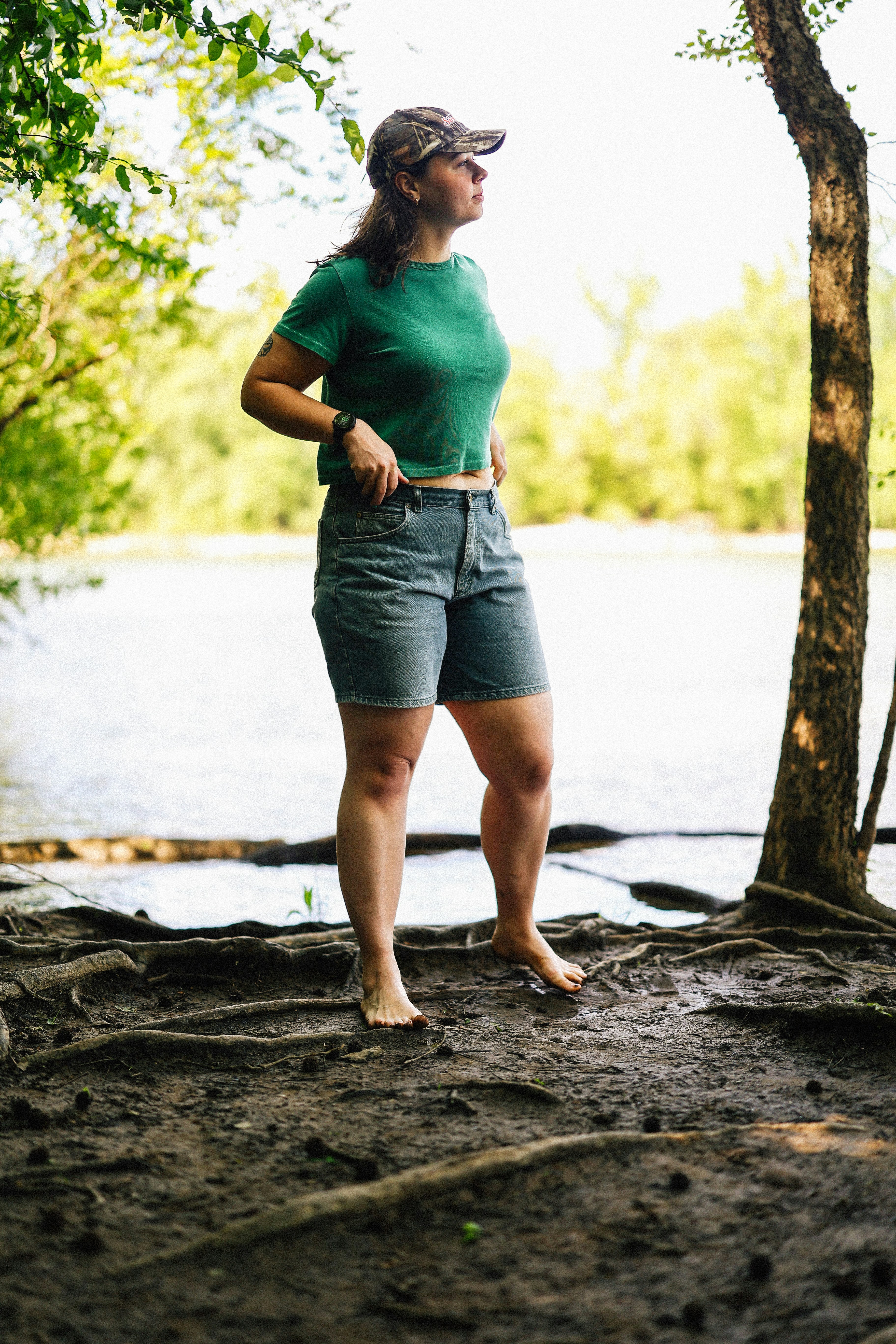 Woman stands near the water, enjoying nature.