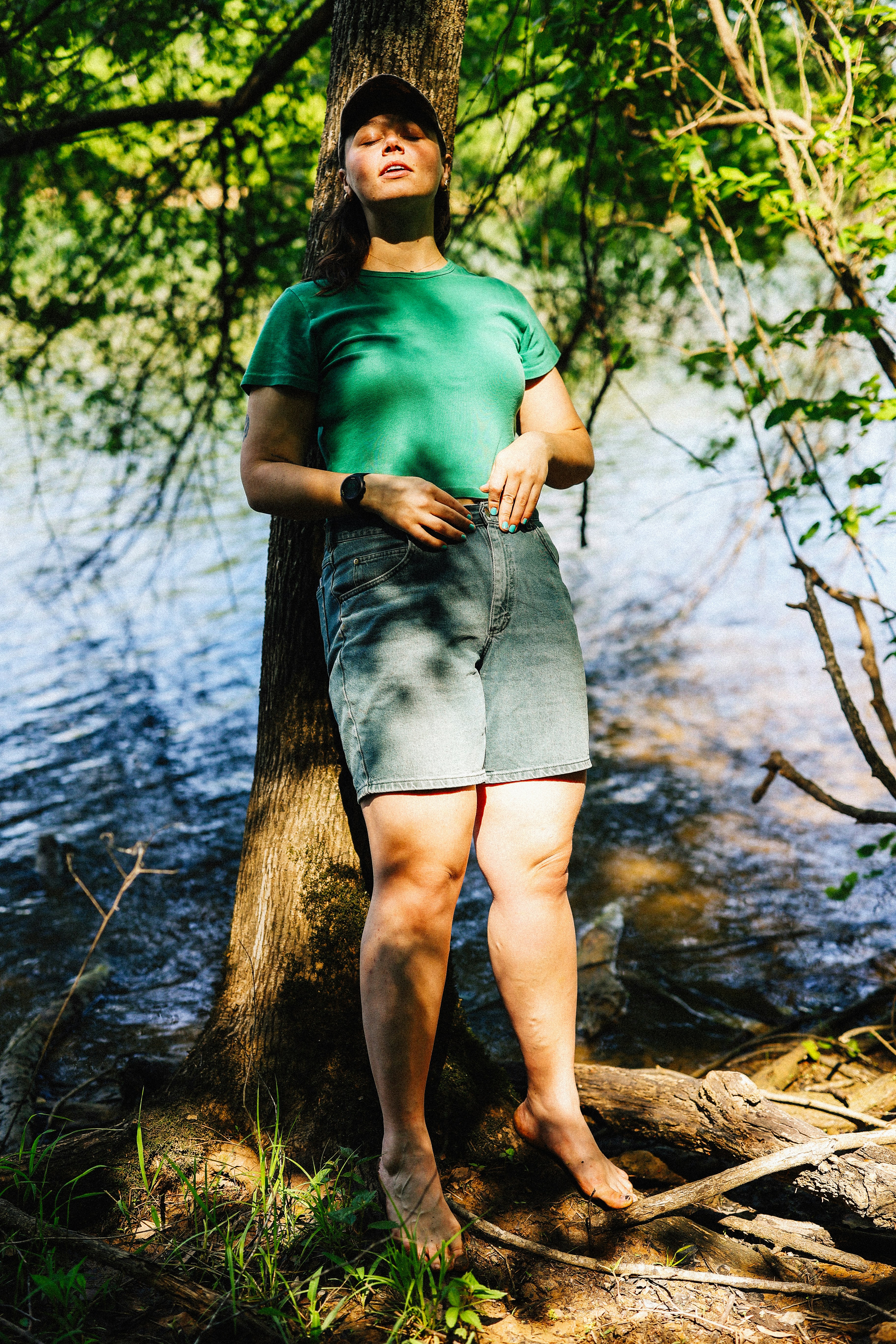 Green-shirted silhouette by the lakeside tree