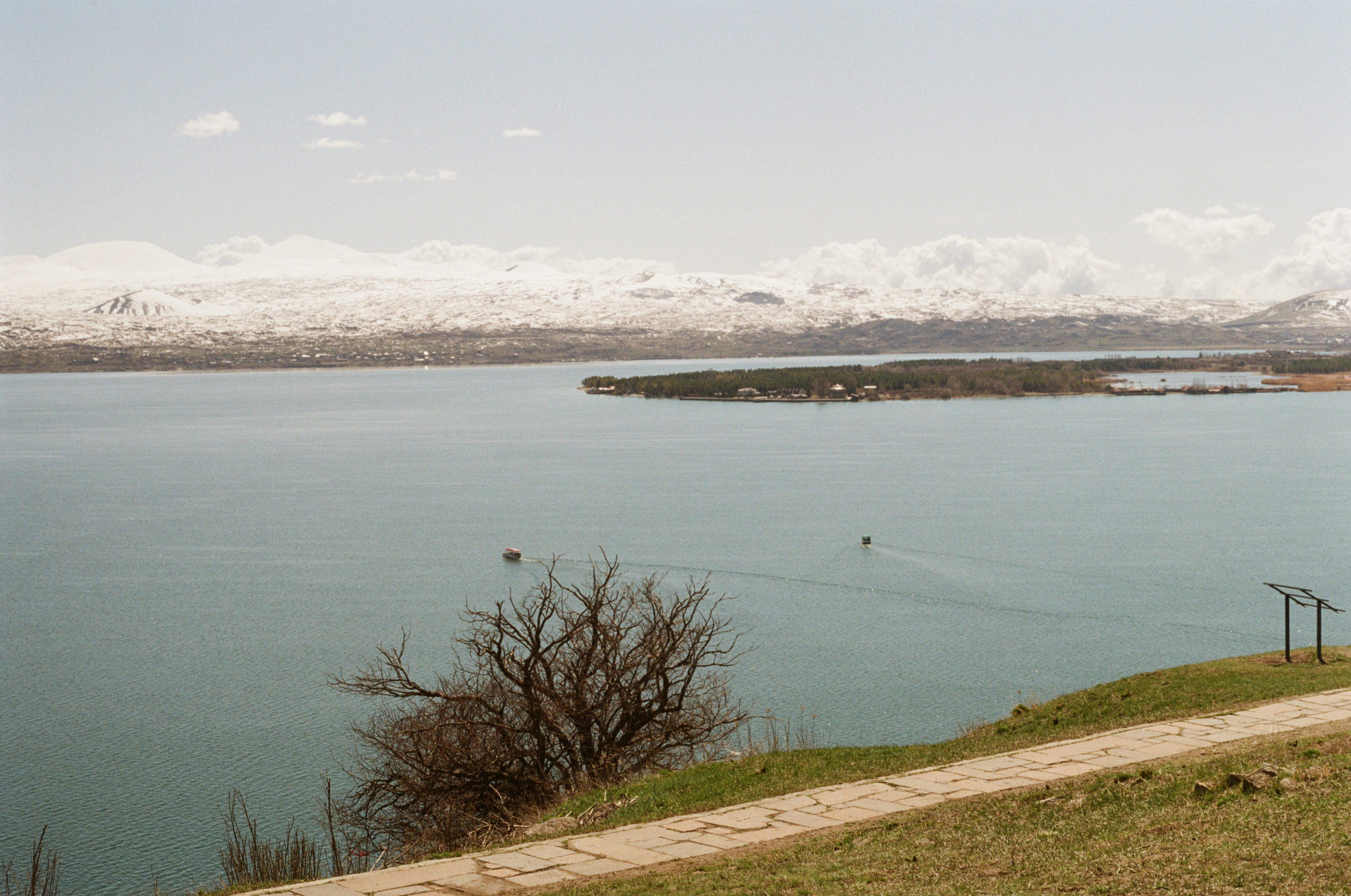 A calm lake reflects snowy mountains in the distance.
