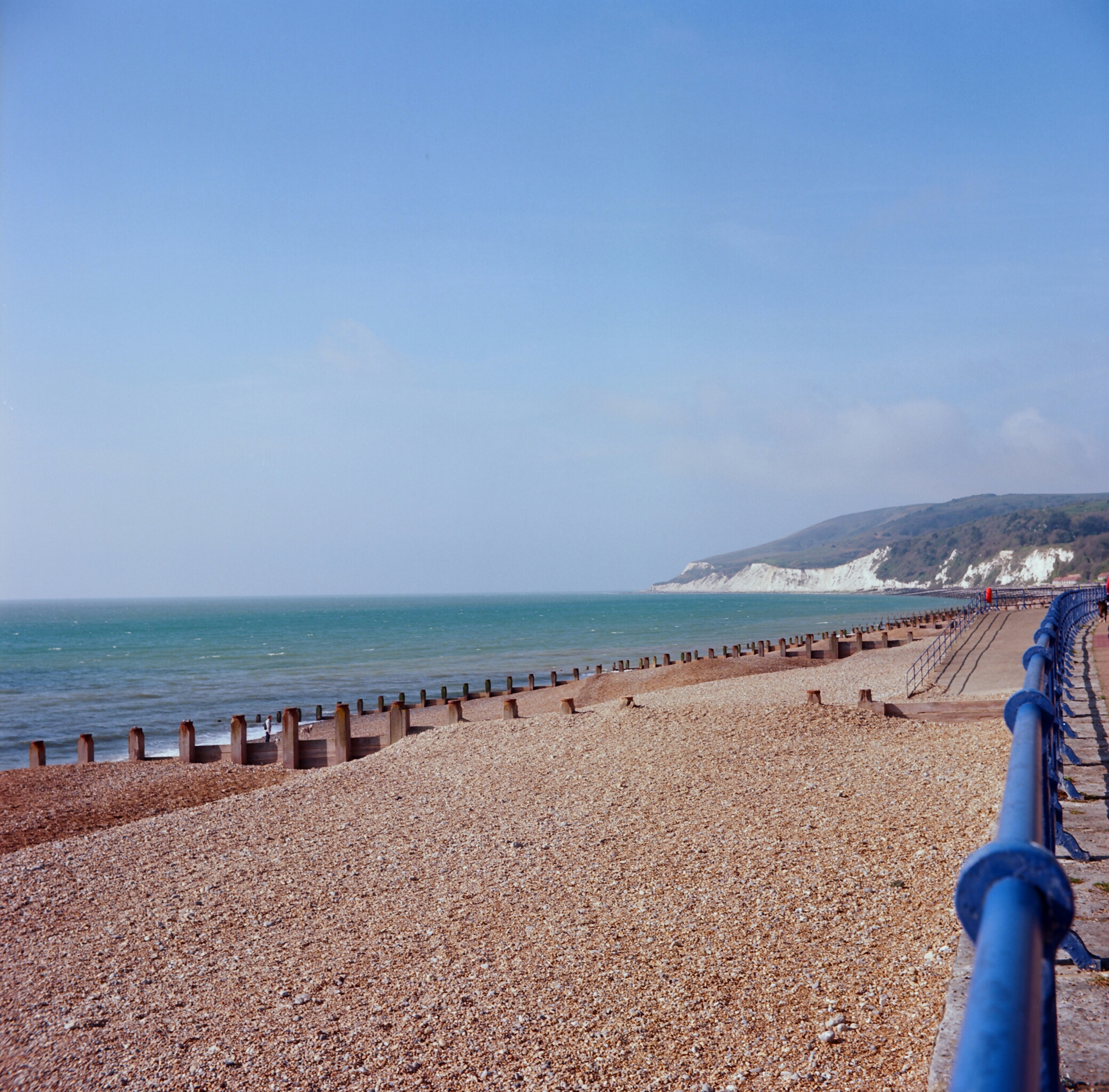 Blue Railing, Tidal Path: A Beach Walk Toward the Cliff Horizon