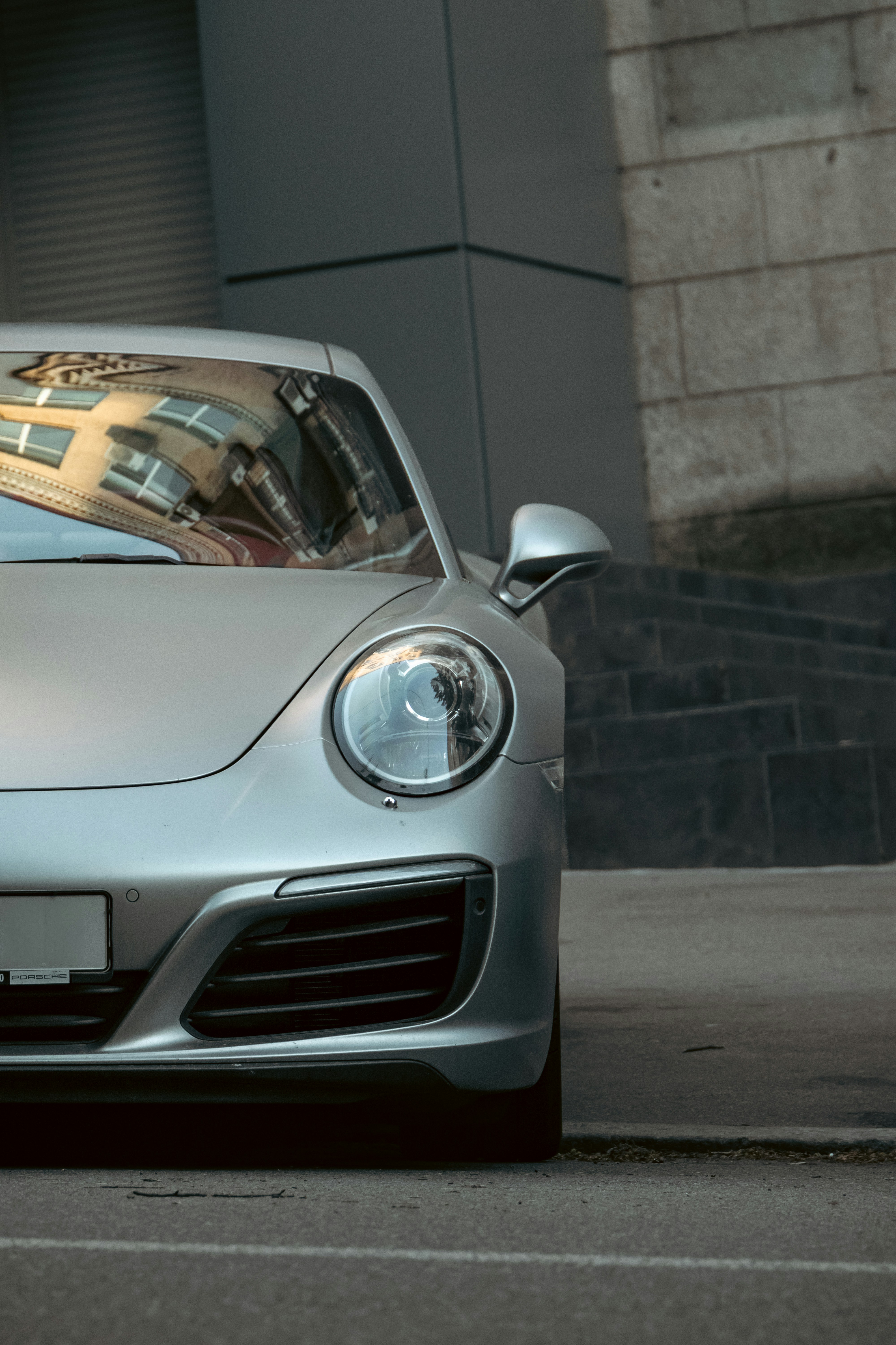 El coche Porsche plateado está aparcado cerca de un edificio. foto ...