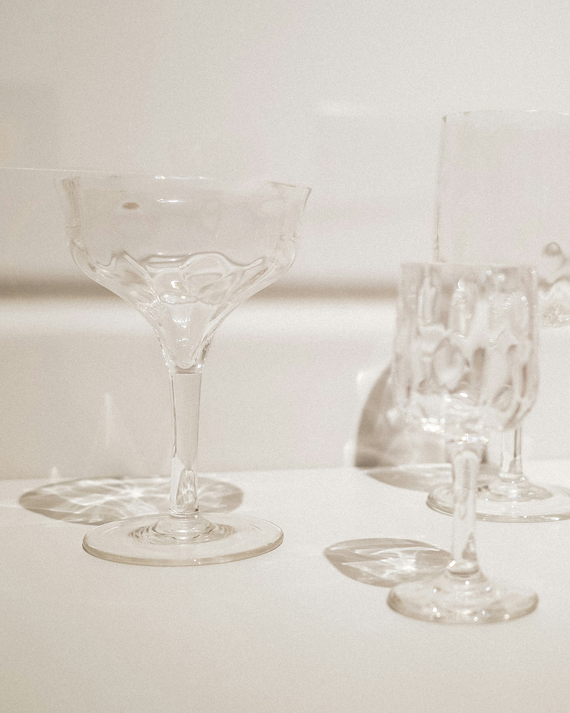 Three intricately designed glassware pieces casting soft shadows on a minimalistic surface.