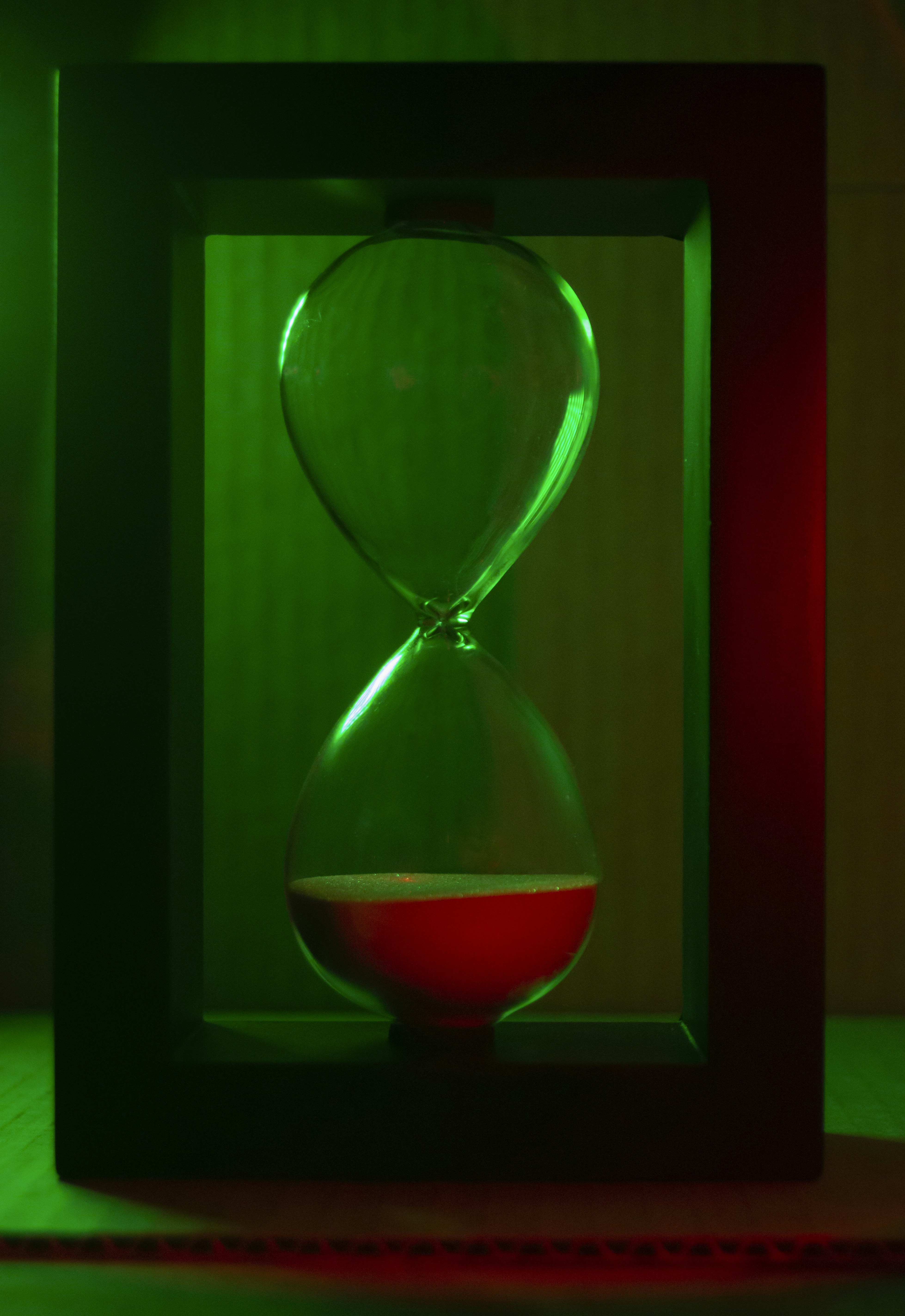 Green-lit hourglass with red sand trickling down. photo – Free Time ...