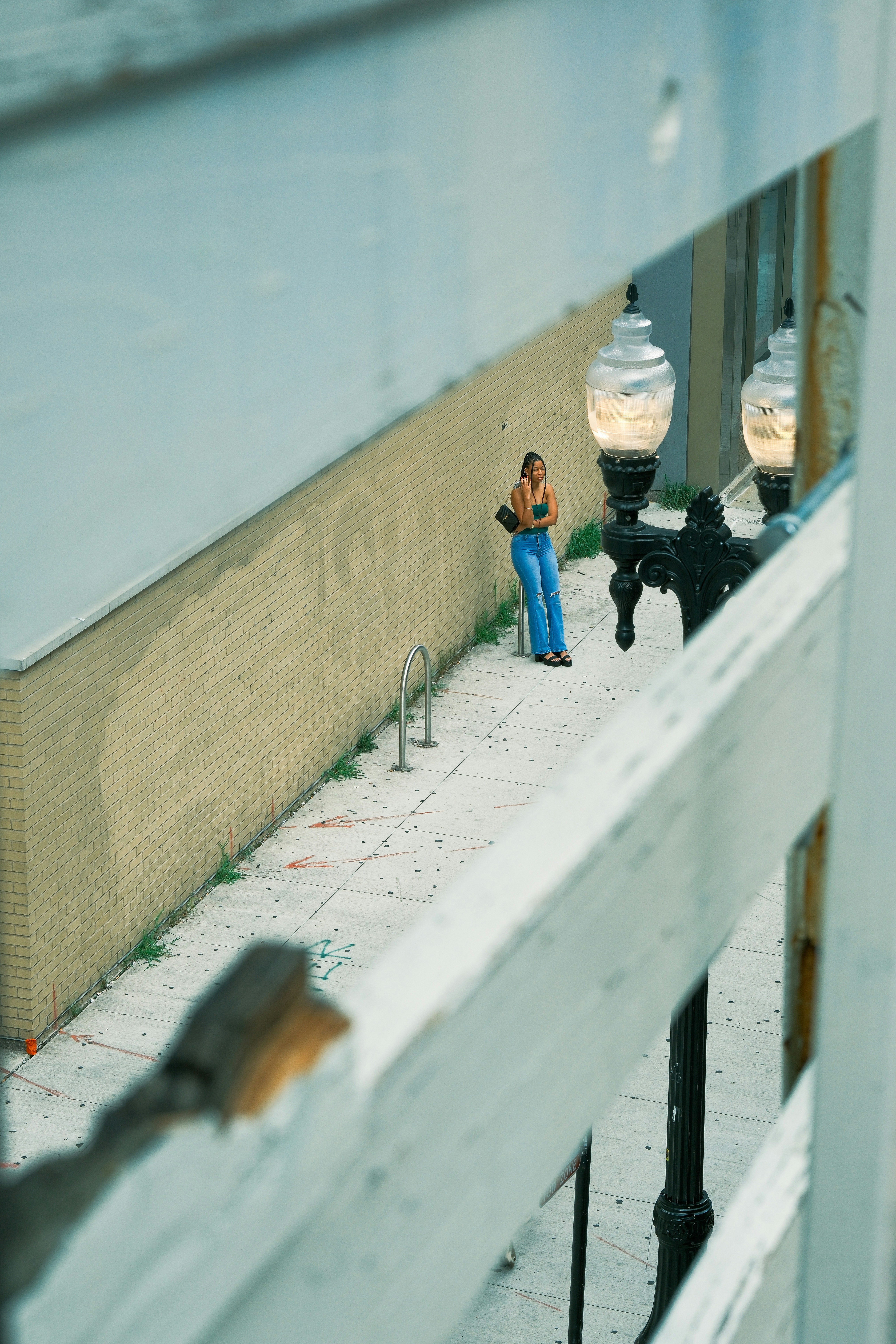 Urban Echoes: A Woman in Blue Jeans Beside a Dim Streetlamp