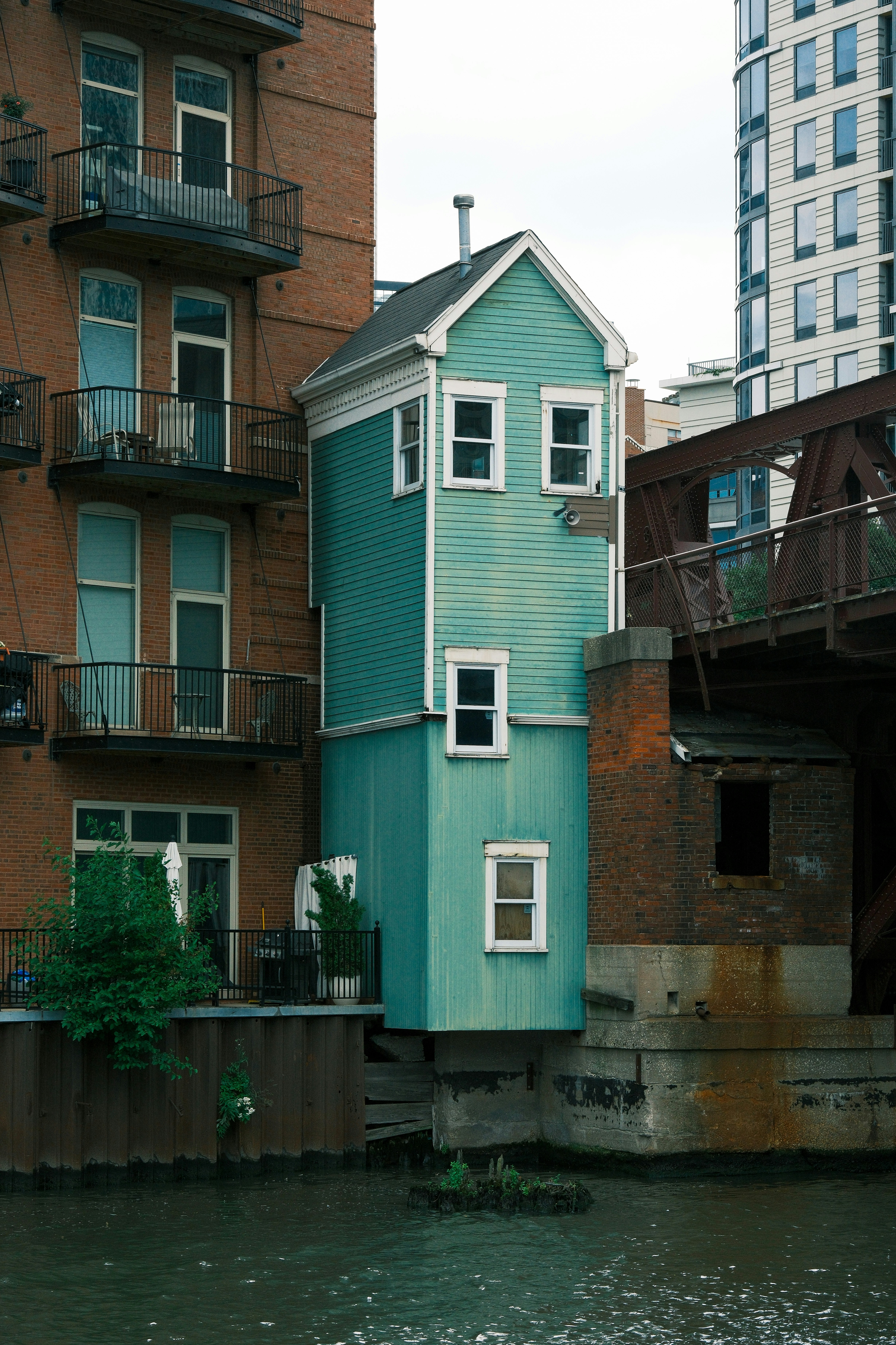 A small, blue house sits between buildings. photo – Free Architecture ...