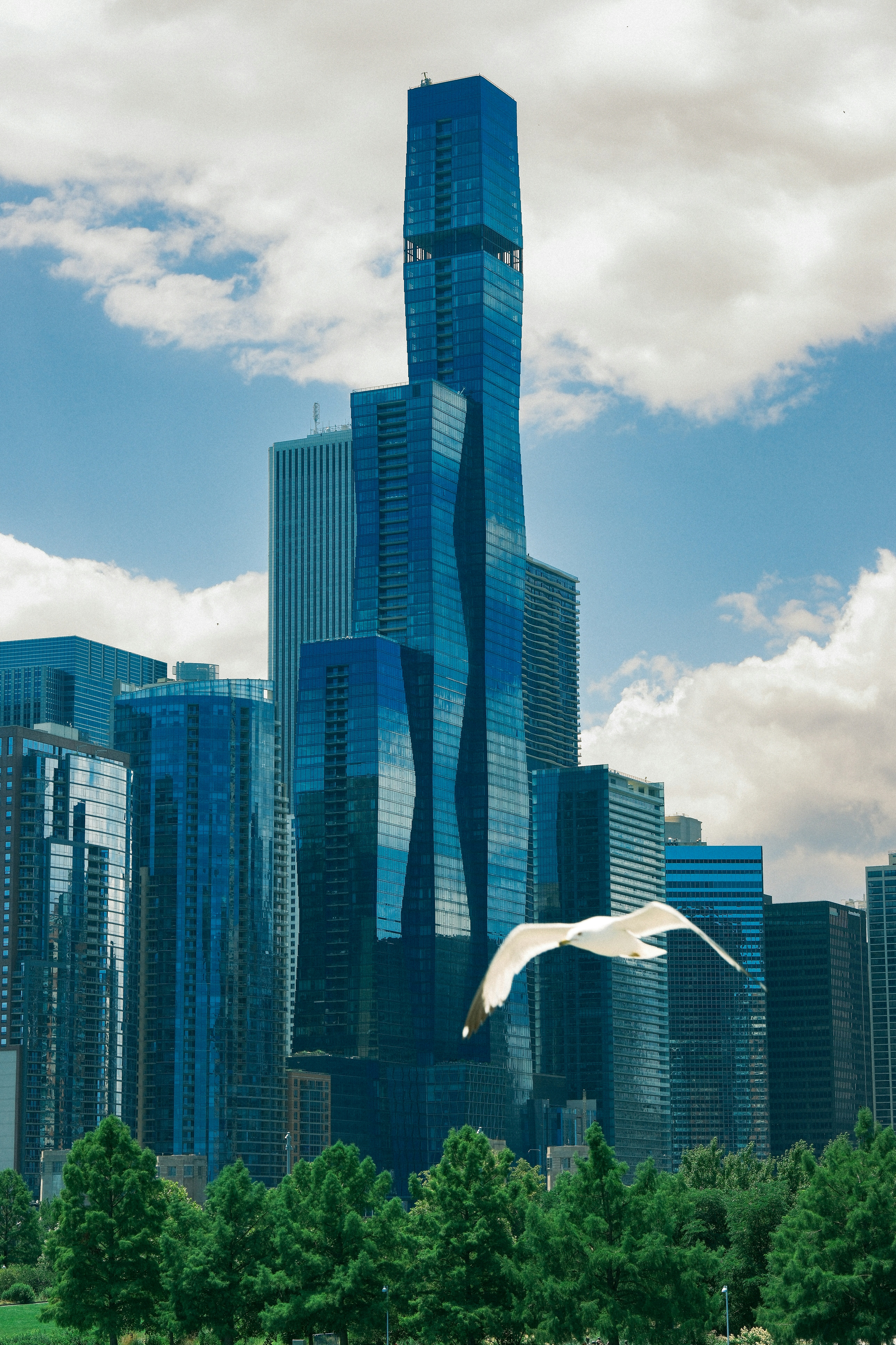 Blue Glass Ascension: The Torsion Tower Rises Over a Green Park
