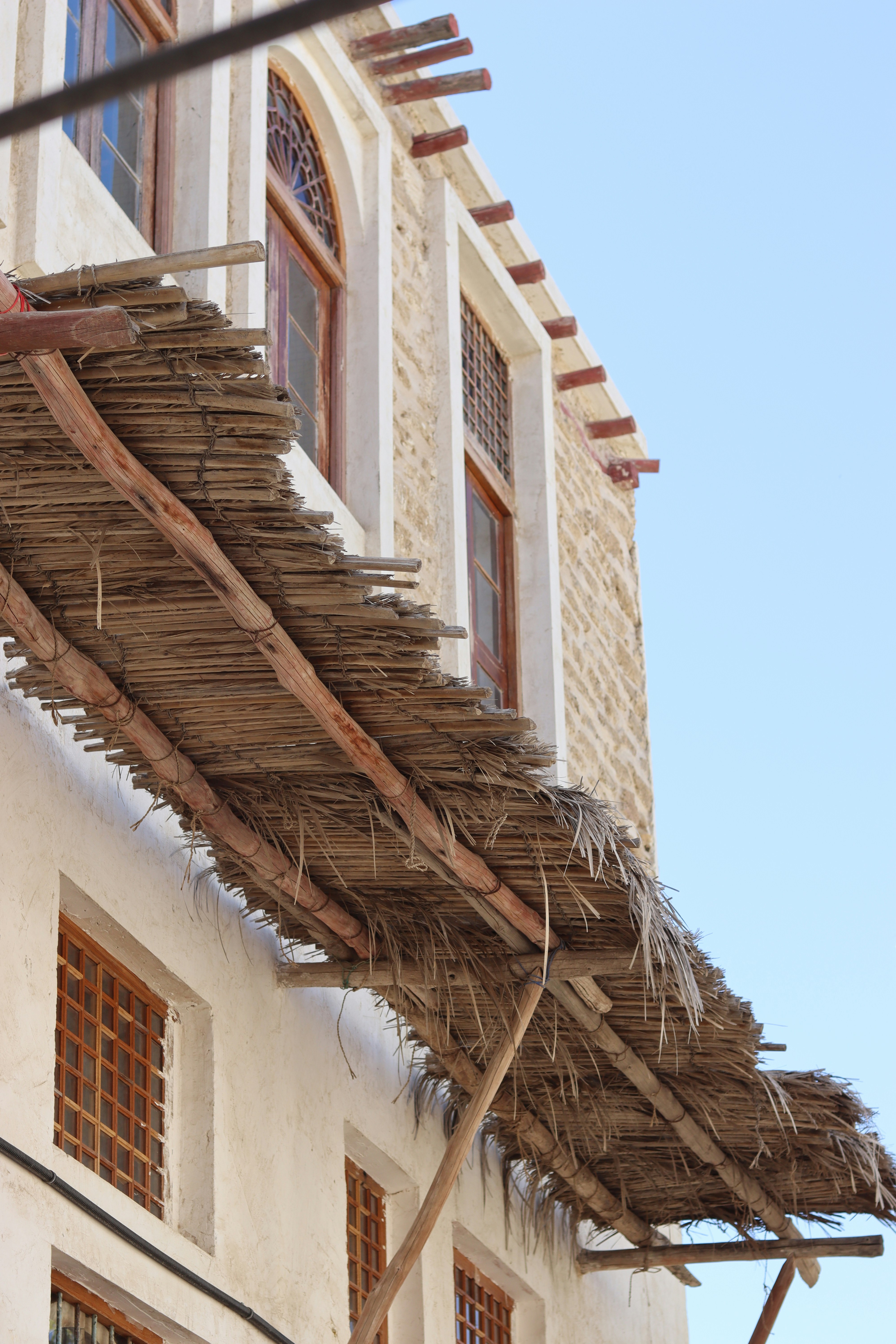 Thatched Overhang Weaves Texture Along a Coastal Facade