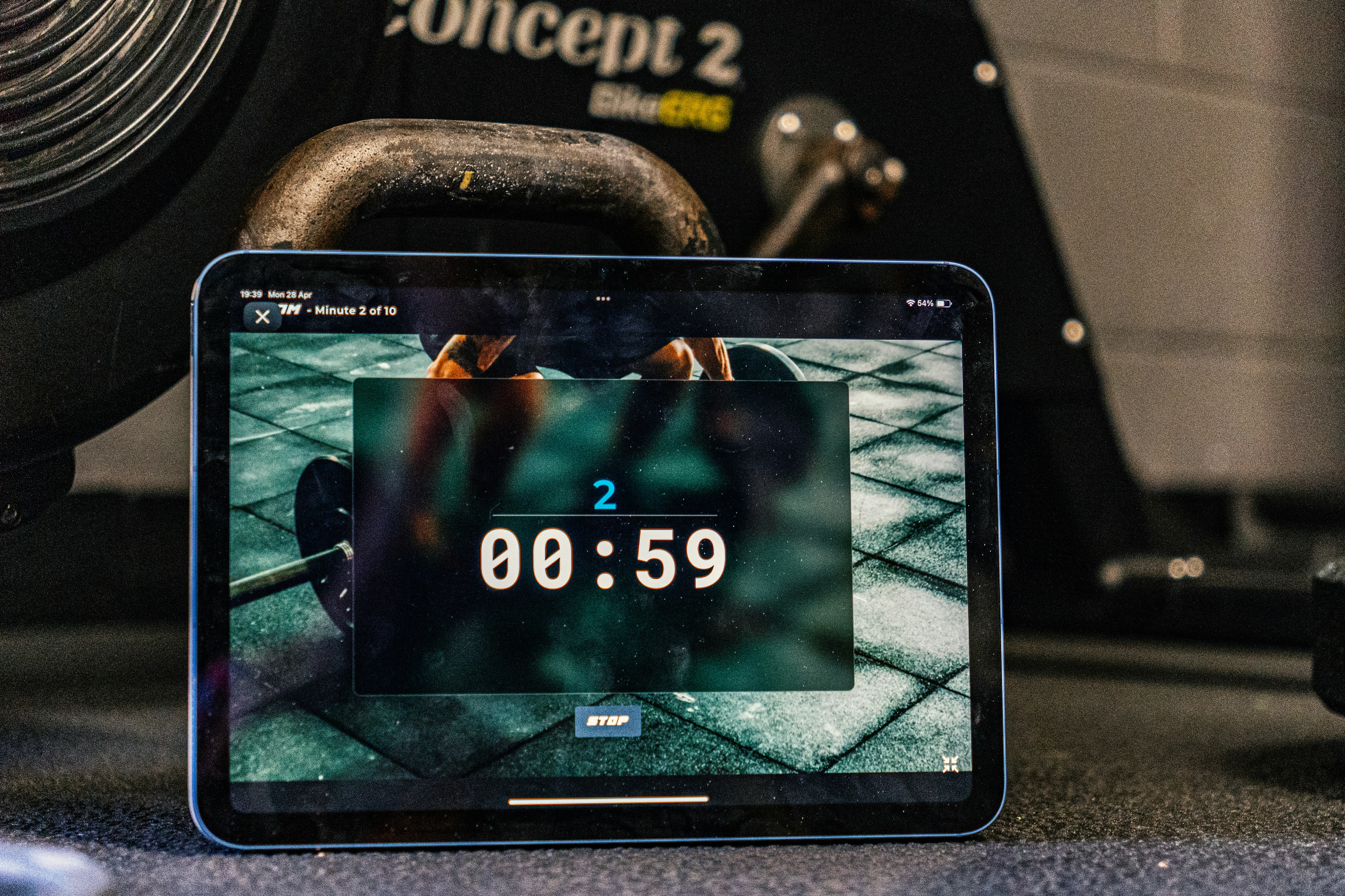 Tablet displays a timer, with workout equipment in background. photo ...