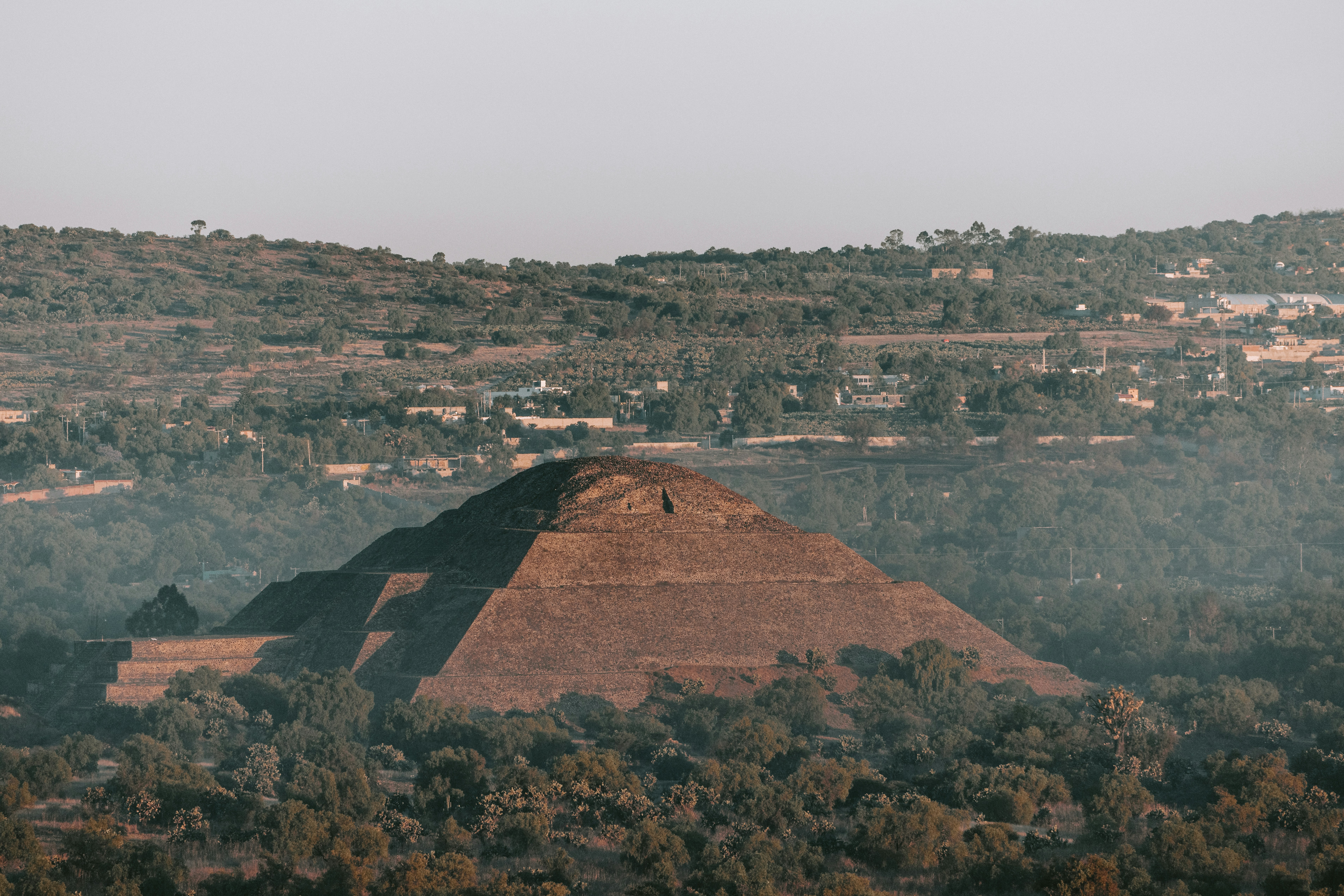 Ancient pyramid structure rising above a lush landscape, shrouded in morning mist. The scene captures the timelessness of historical architecture.