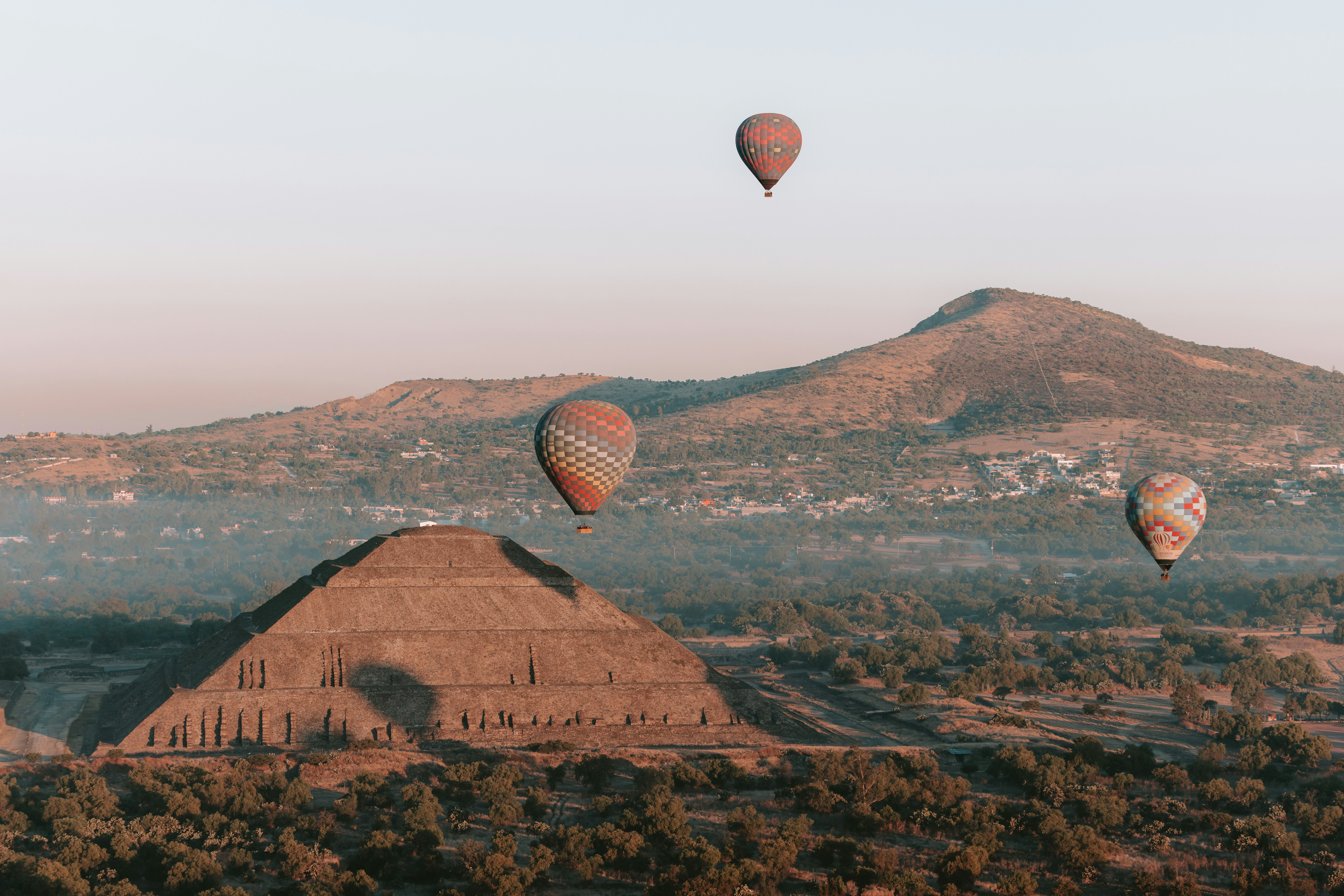 Dawn Balloons Over a Desert Ridge and Pyramid‑like Monoliths