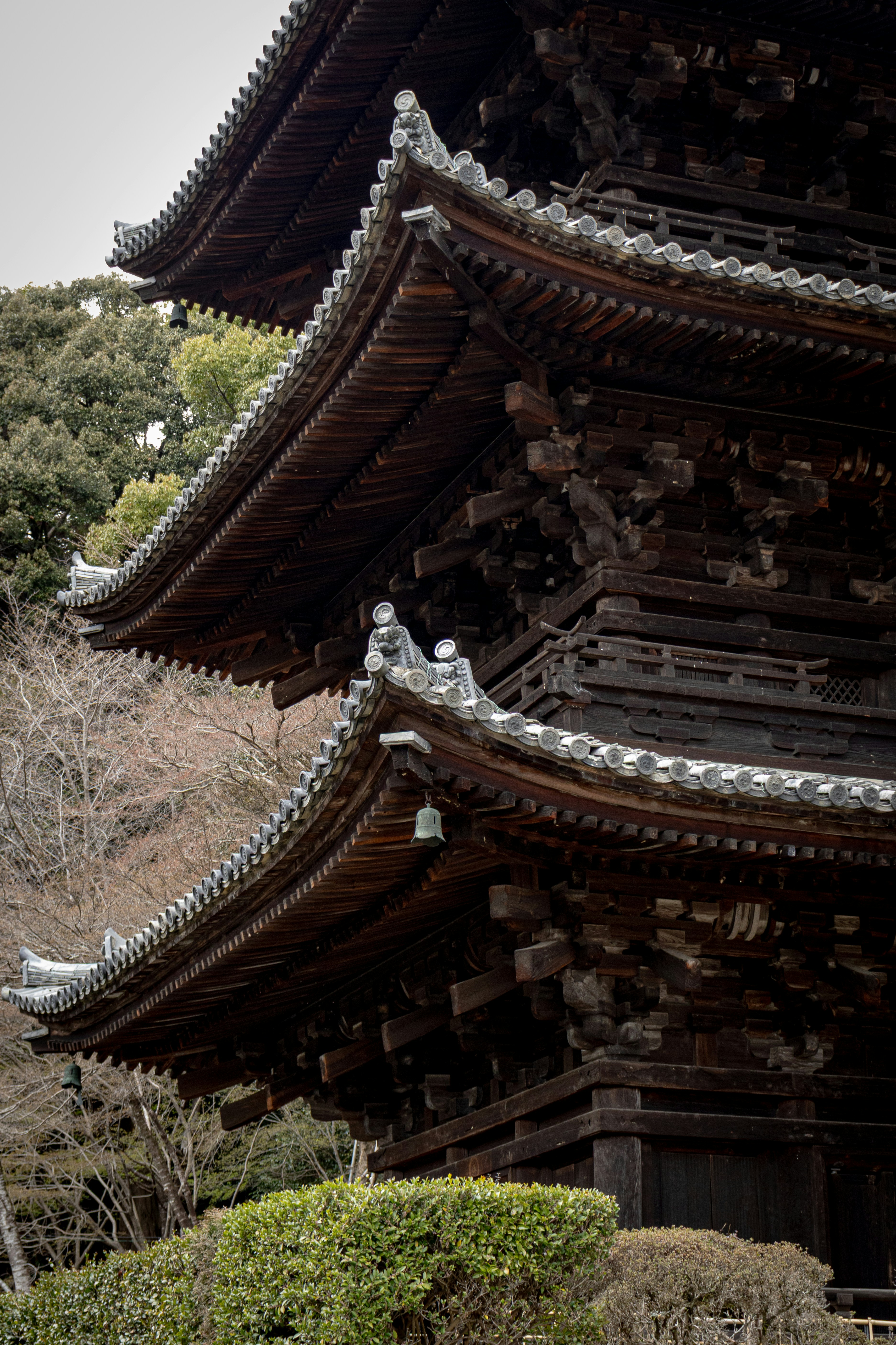 Intricate wooden pagoda showcasing traditional Japanese architectural design surrounded by lush greenery.
