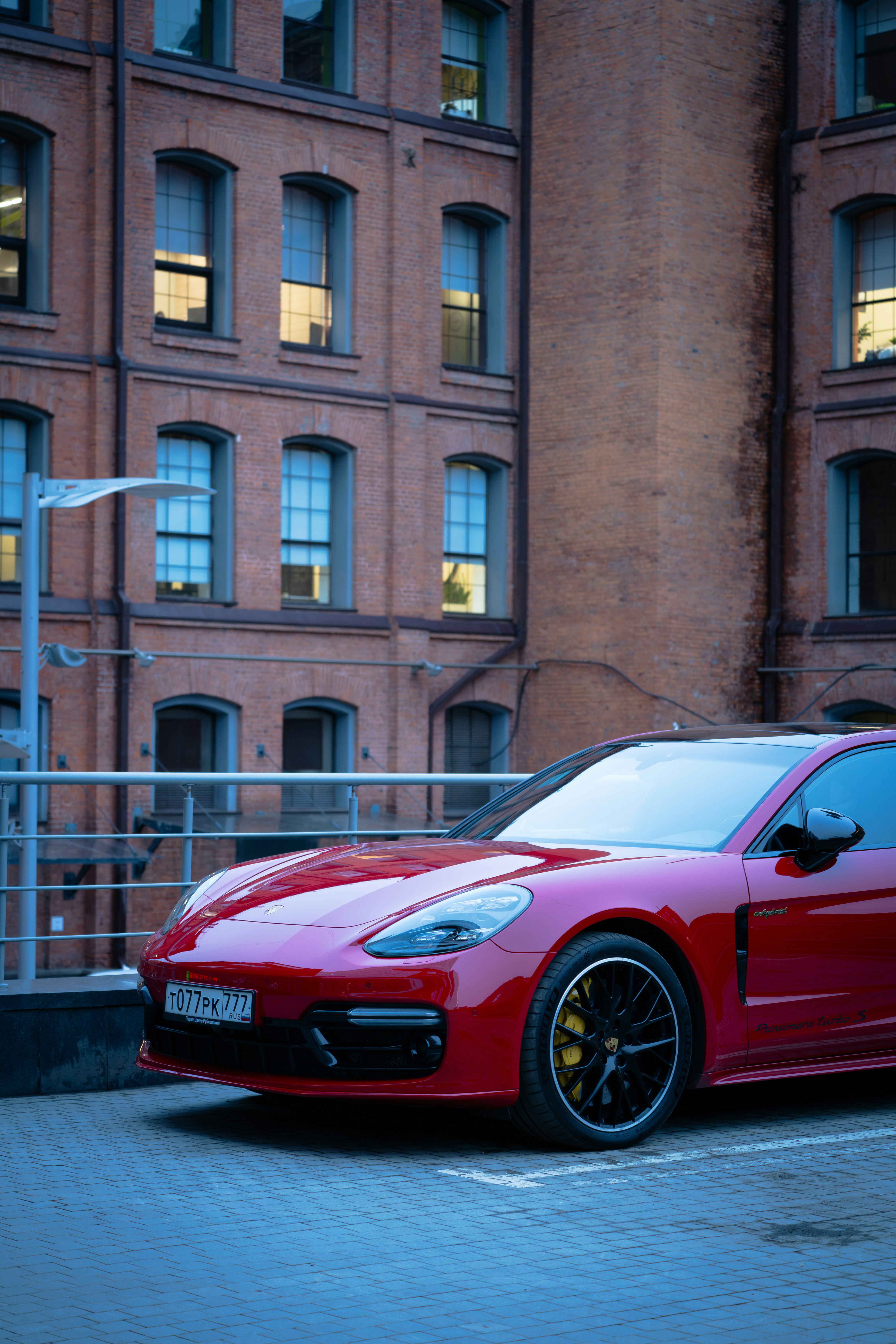 Crimson Porsche in an Urban Brick Backdrop, Bathed in Evening Light