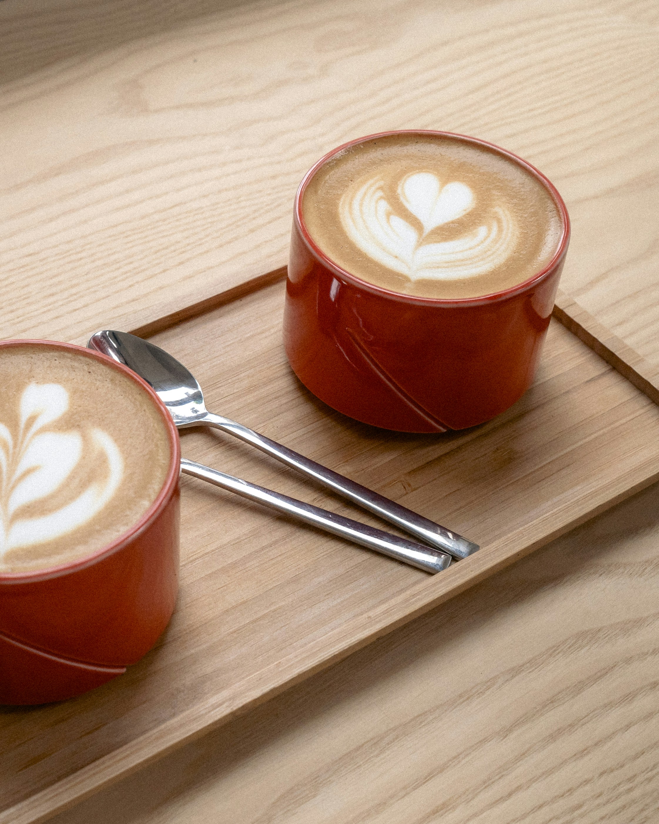 Crimson Mugs and Heart-shaped Latte Art on a Wooden Tray
