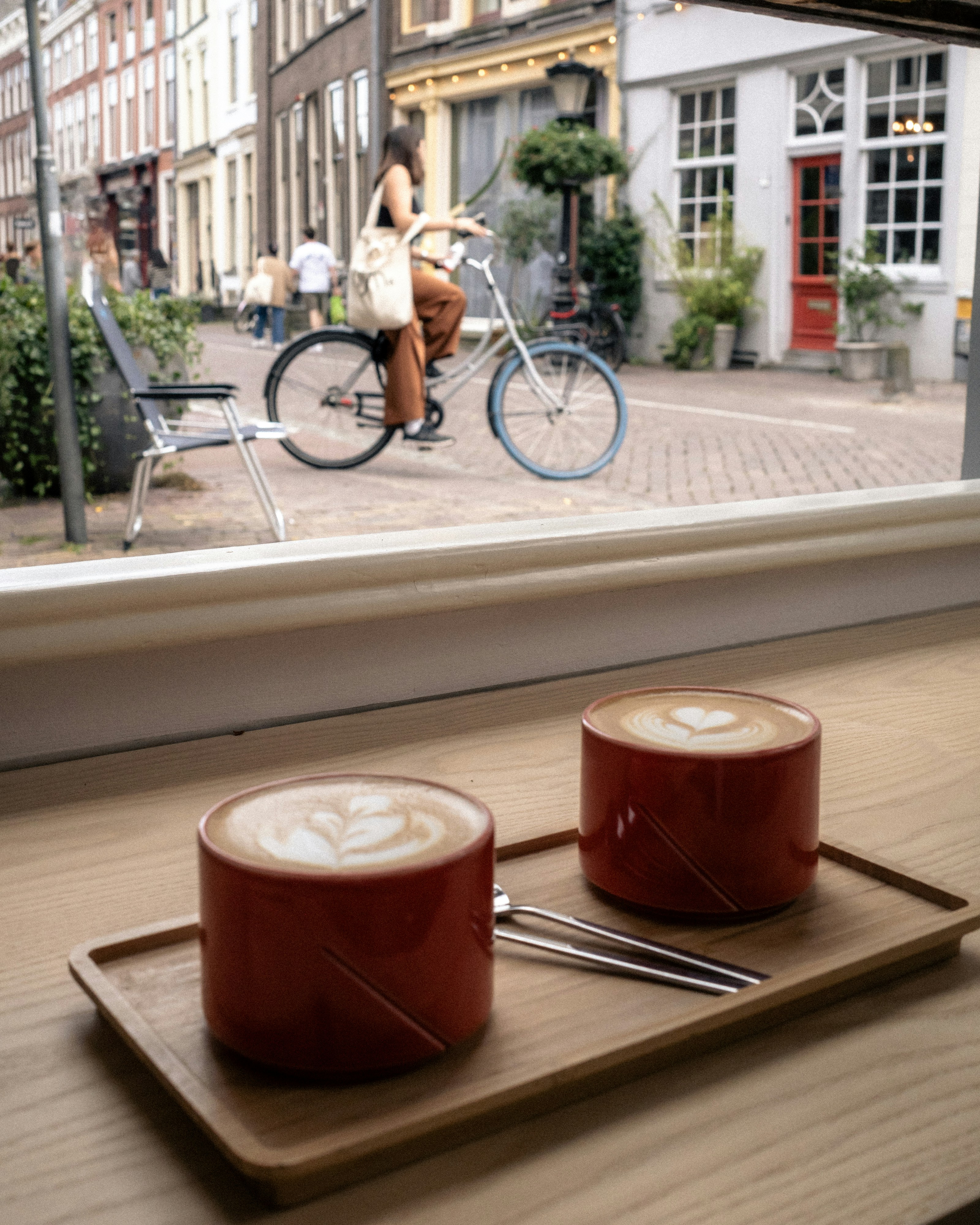 Coffee cups sit while a cyclist rides by.