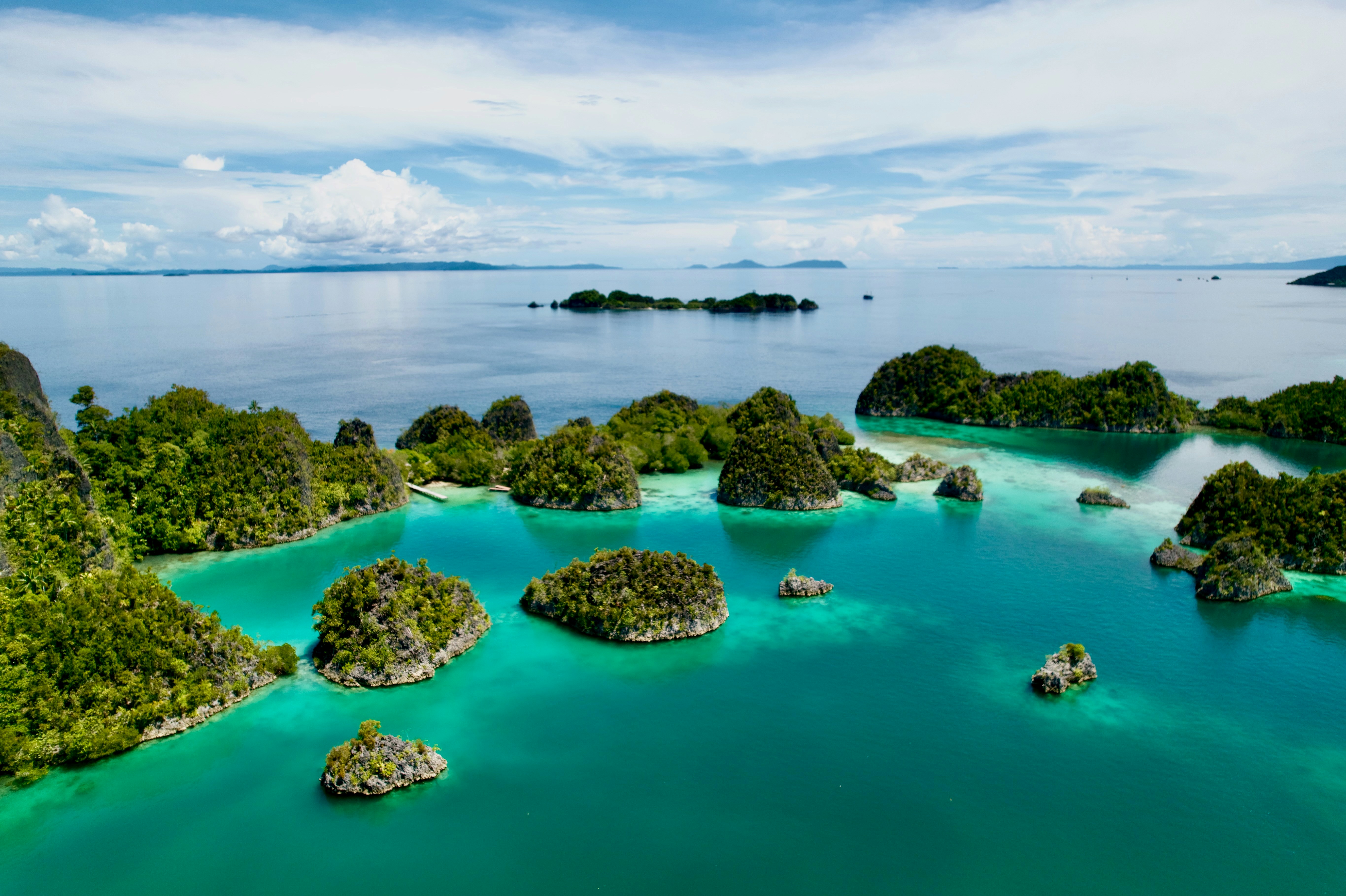 Aerial view of lush green islands surrounded by vibrant turquoise waters in a tranquil seascape. Ideal for showcasing the beauty of nature's untouched landscapes.