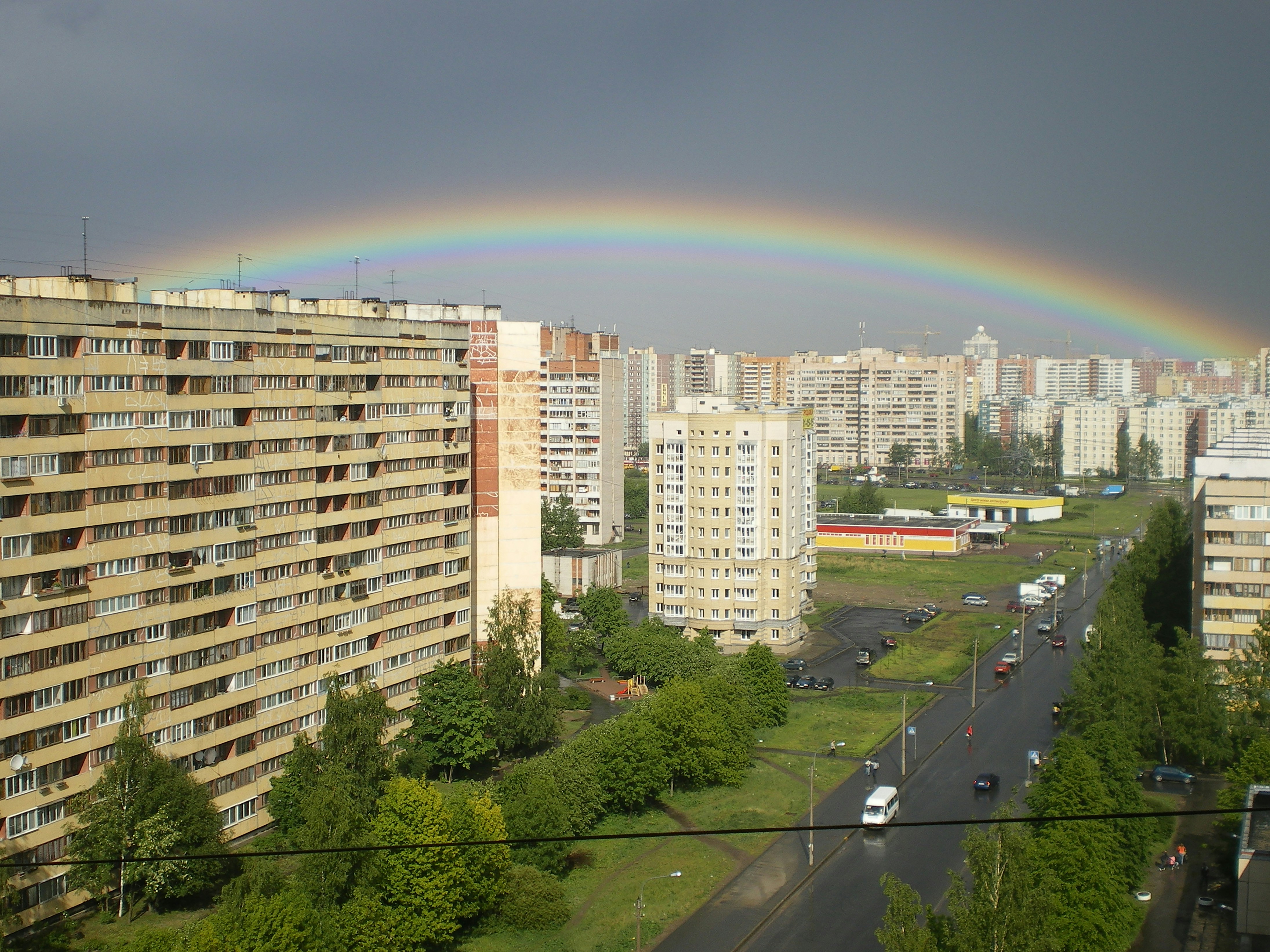 Arc Across the City: Rainbow Over Towers and Tree-Lined Streets