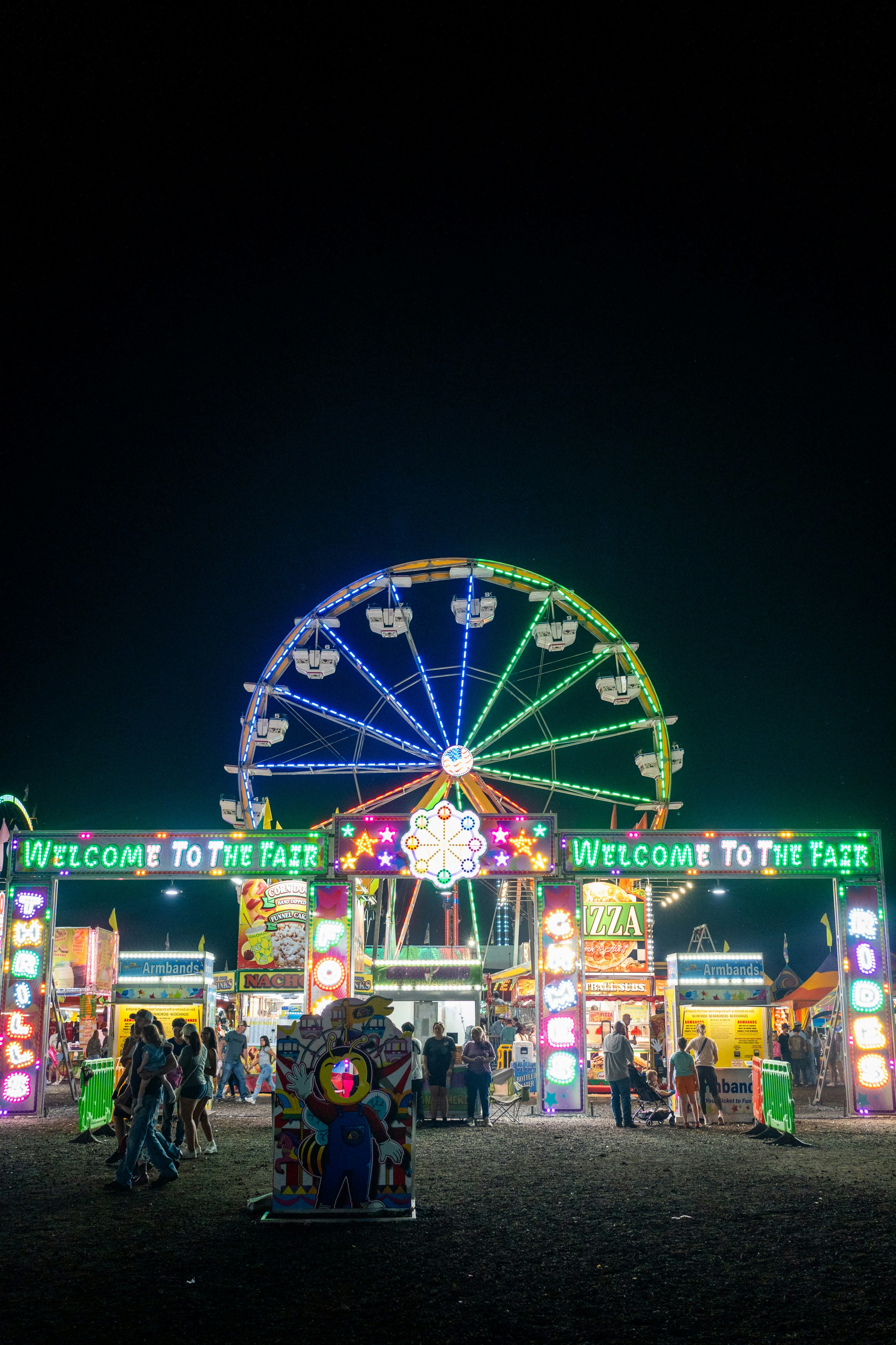 A nighttime fair welcomes guests with lights.