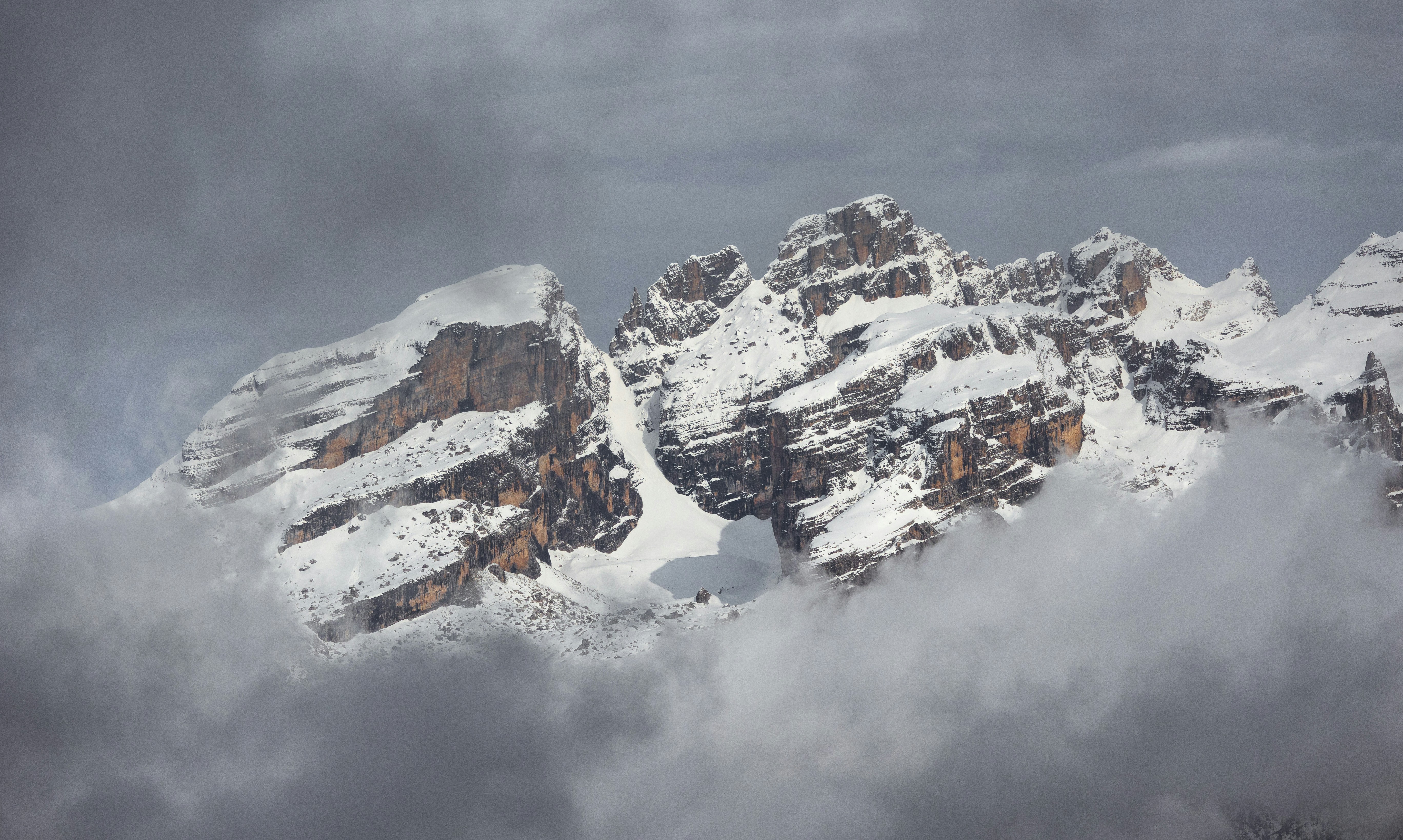 Cloud-veiled Summit: Snow-Kissed Peaks Rising from the Mist