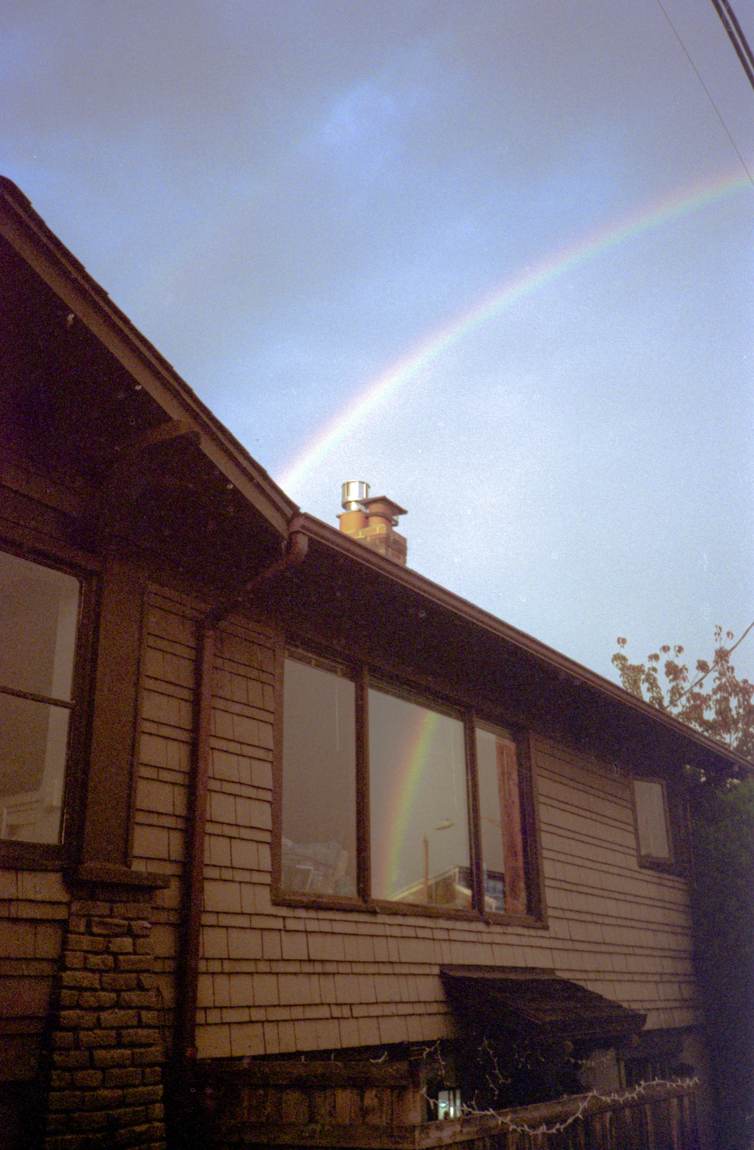 A rainbow arches over a home's roof. photo – Free Image on Unsplash