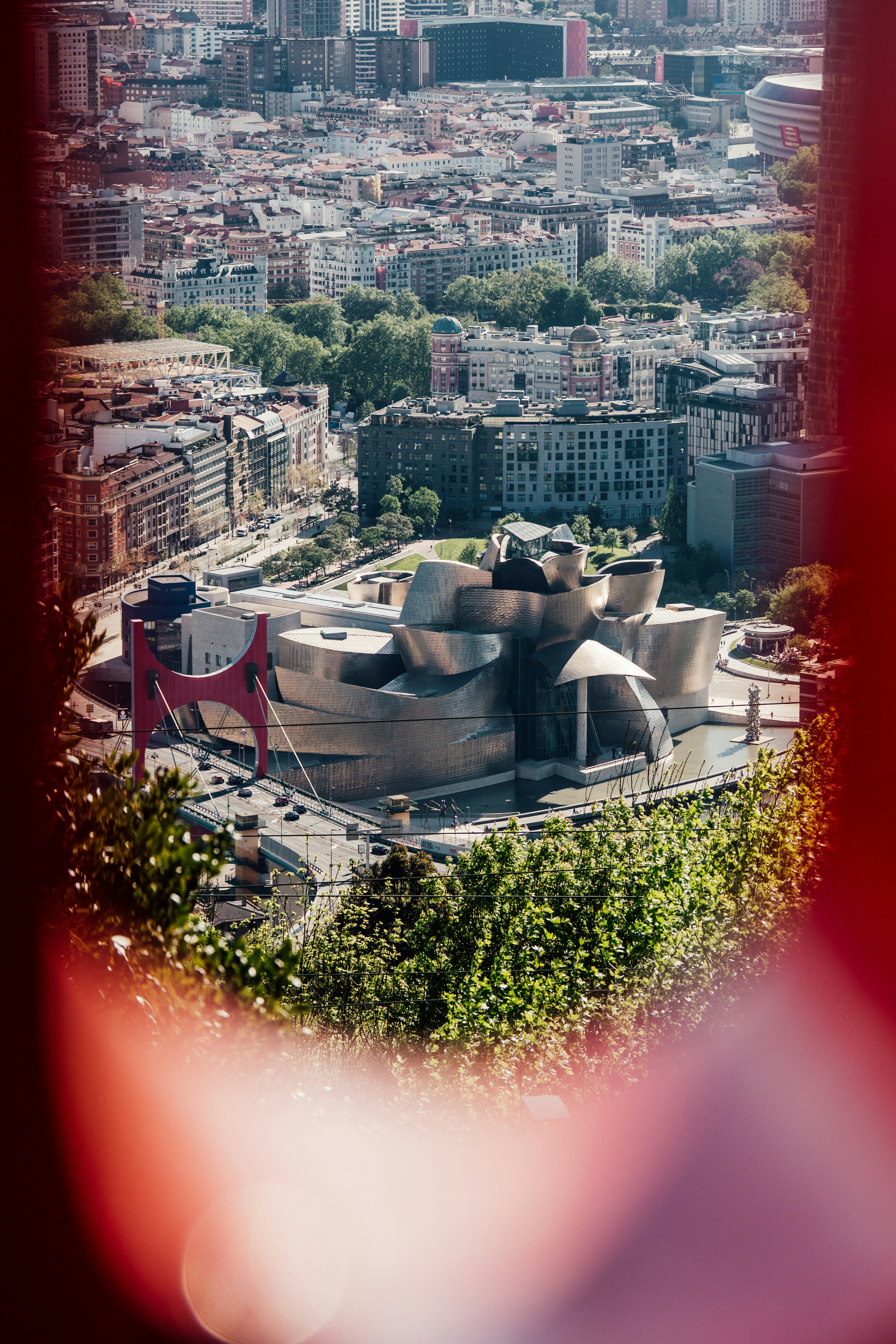 Gehry in the Frame: Bilbao's Titanium Cityscape Through a Crimson Veil
