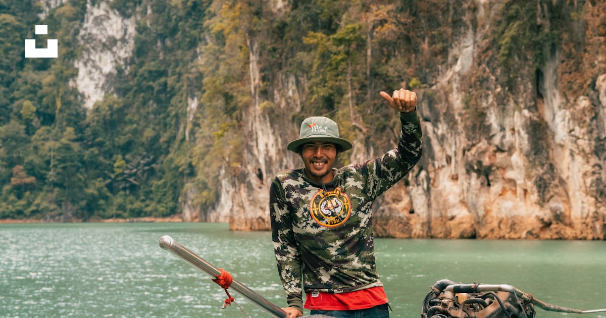 山の景色を眺めながらボートの上で身振り手振りをする男性。の写真 Unsplashの湖の無料画像