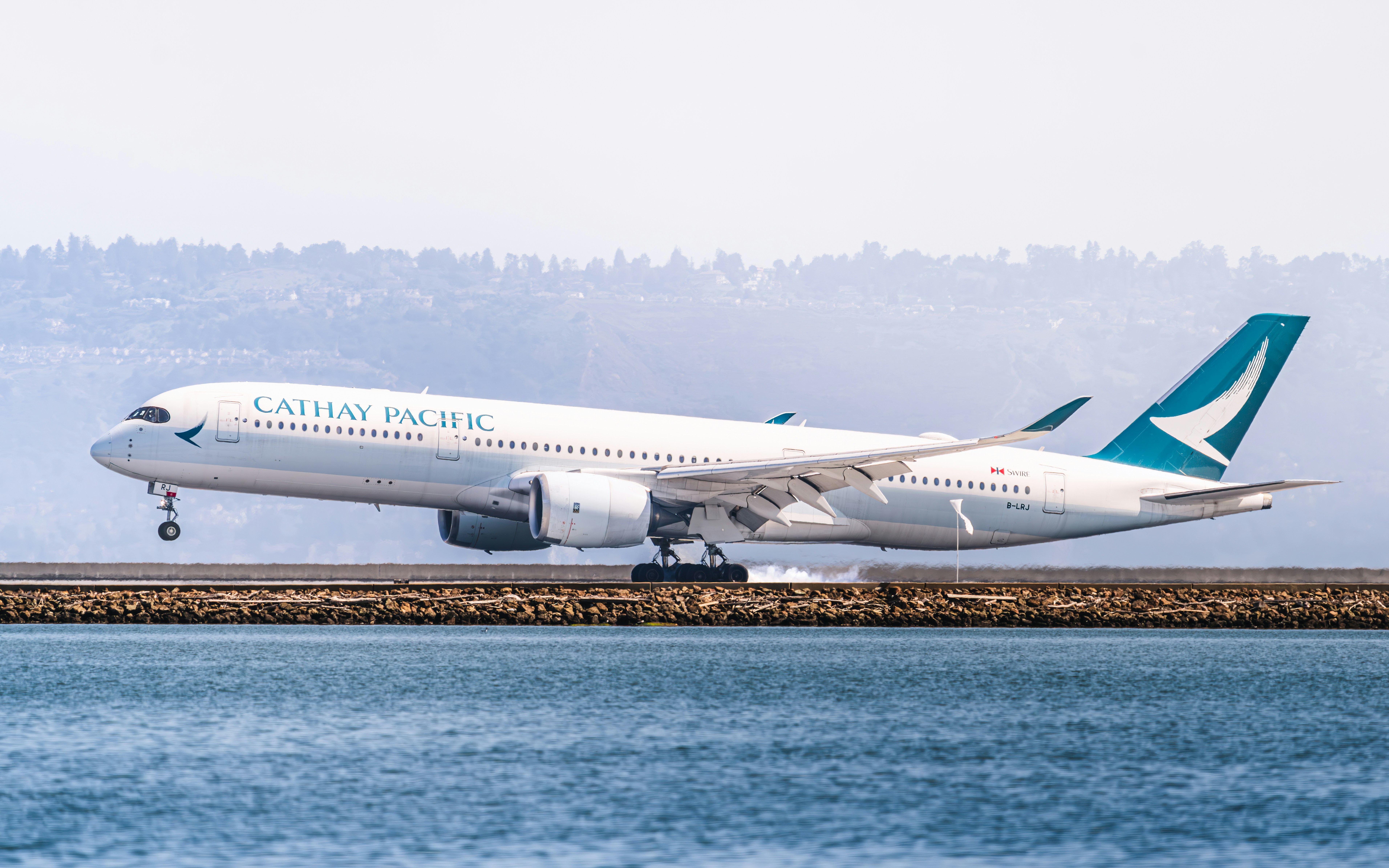 Cathay pacific plane lands near water. photo – Free Plane Image on Unsplash