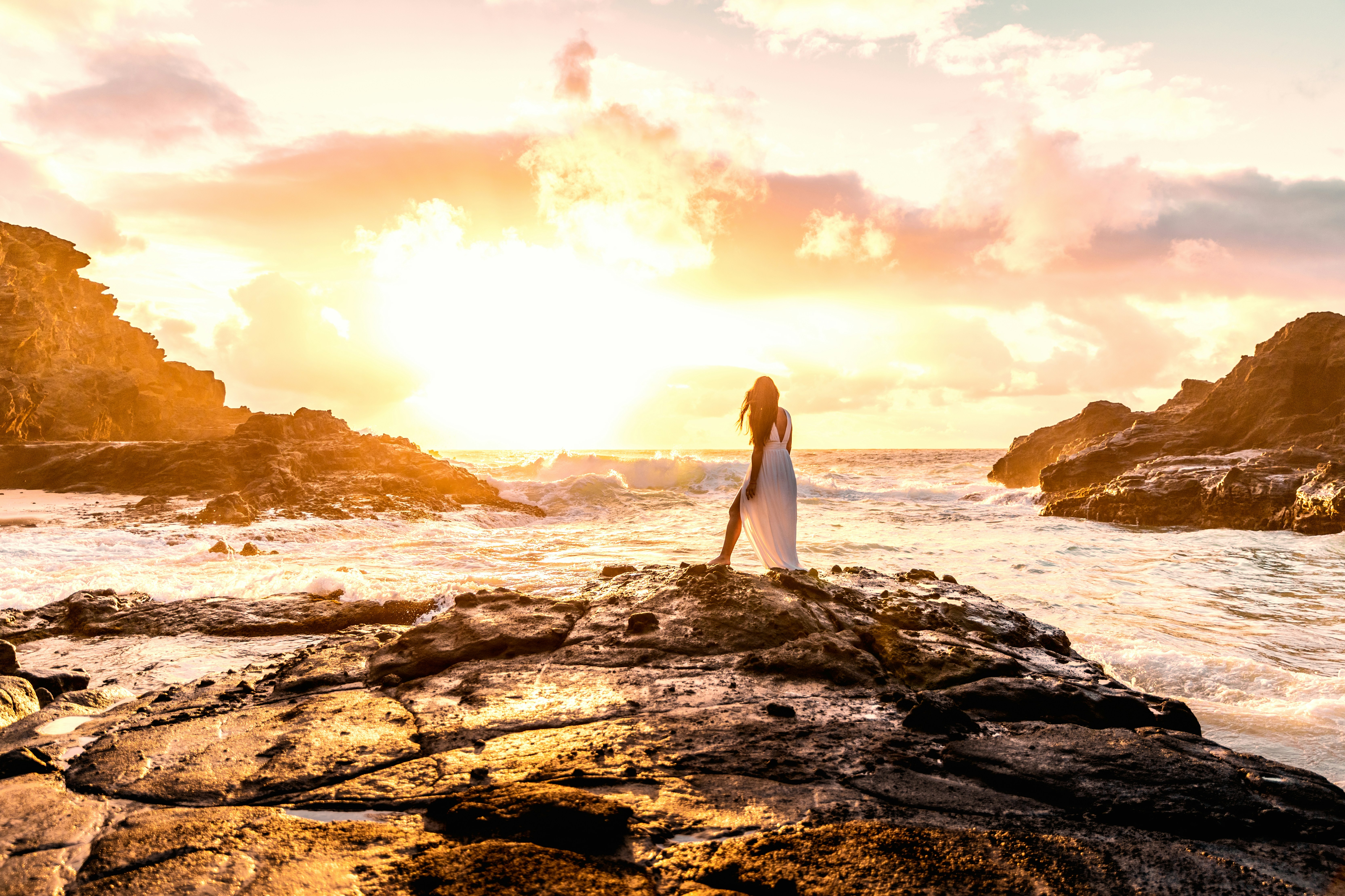 A woman stands on a rock watching the sunset. photo – Free Beach Image ...
