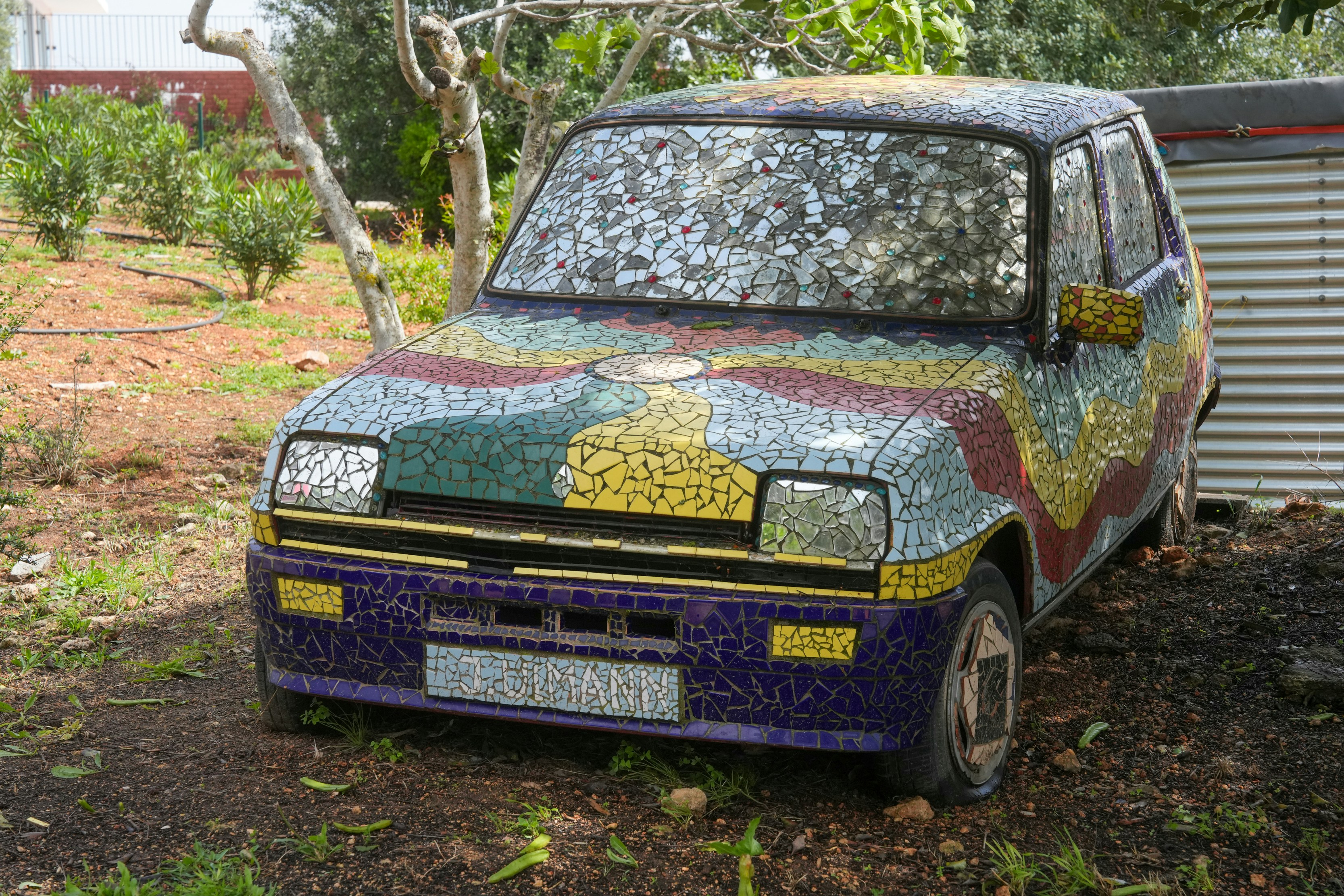 Fragmented Mosaic on Four Wheels: a sunlit compact car wrapped in colorful ceramic tiles