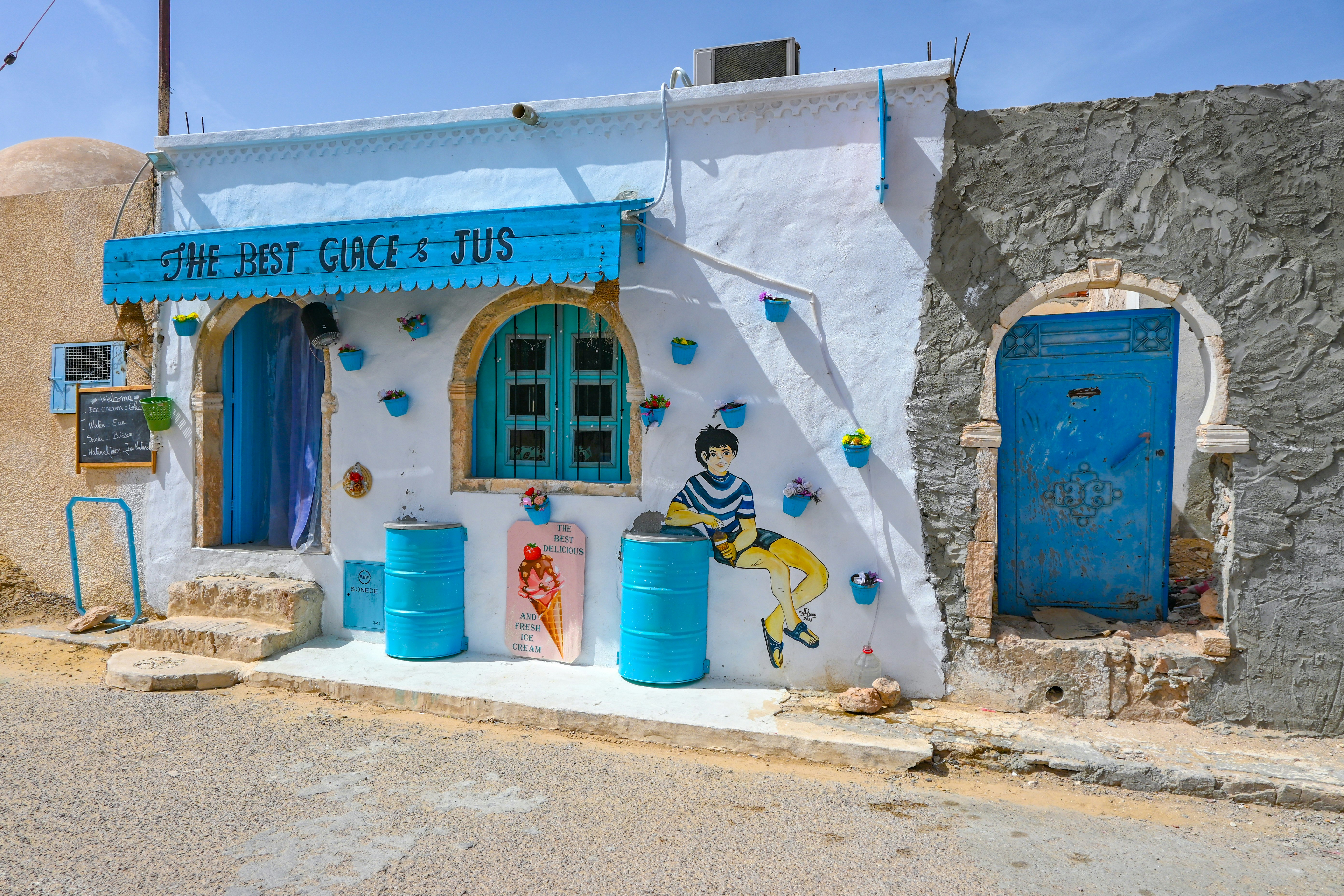 Blue-Washed Facade with a Seated Figure Mural and Turquoise Door
