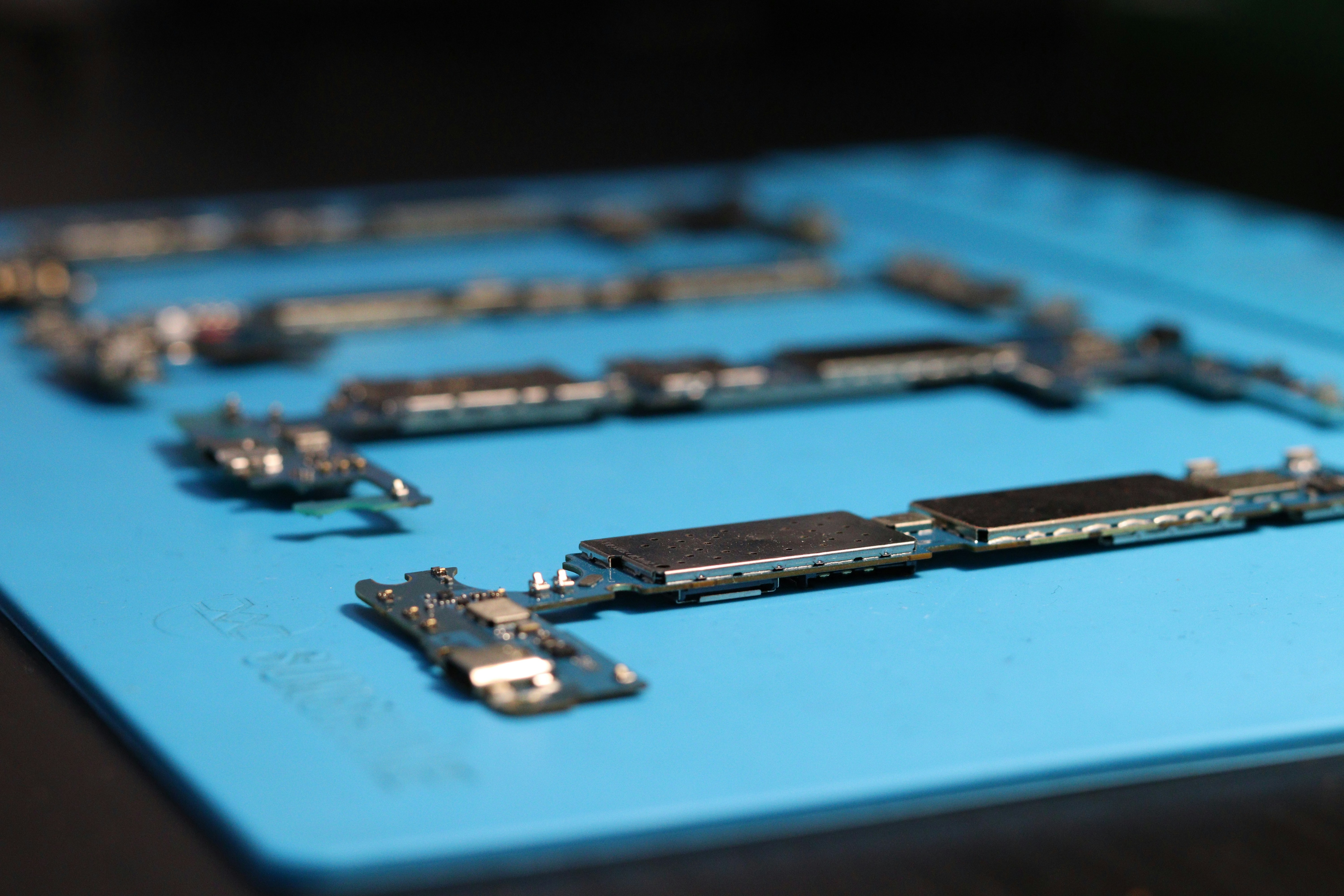 Close-up view of multiple electronic circuit boards arranged on a blue mat, showcasing intricate components and connections.