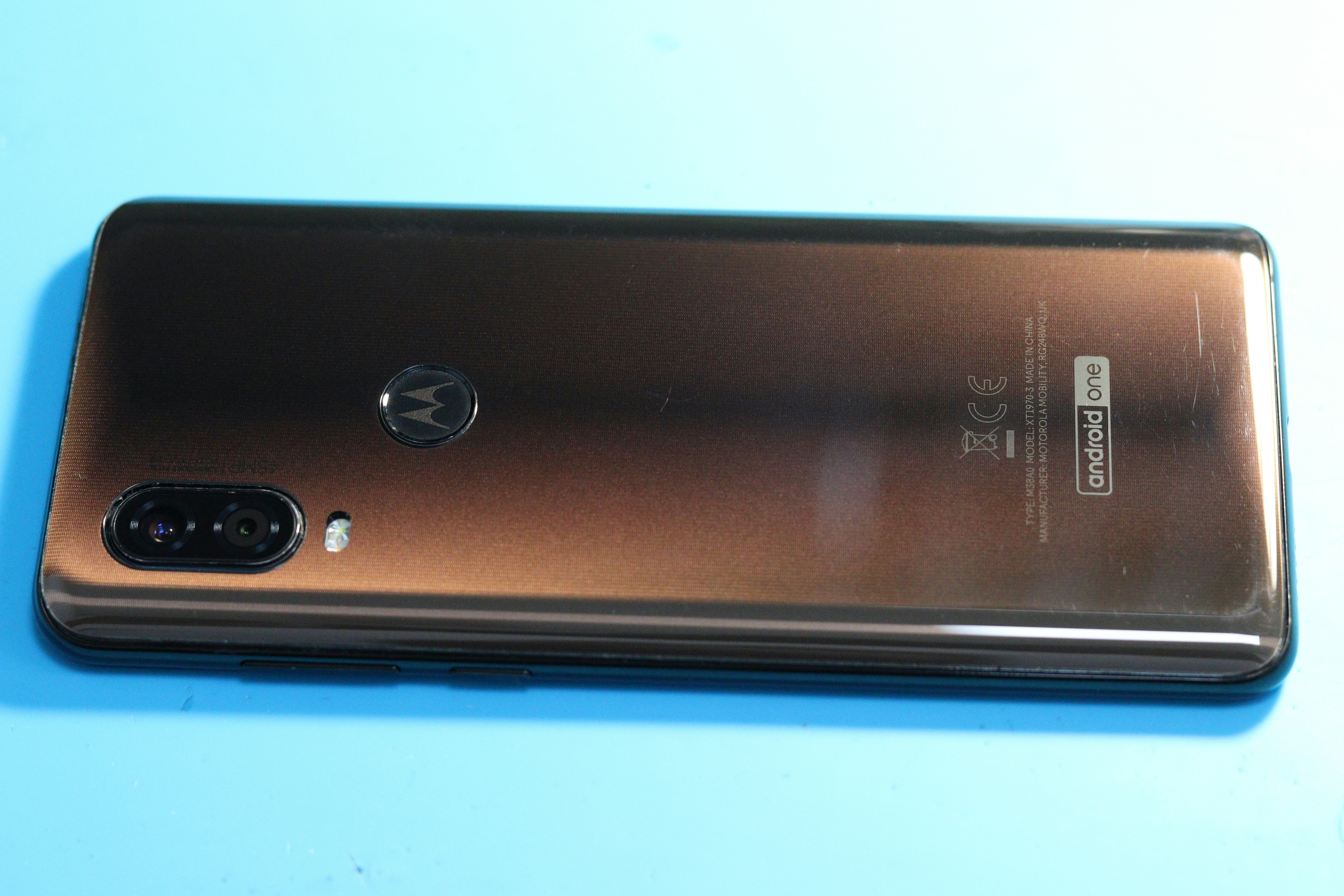Close-up of a Motorola smartphone showcasing its sleek design and dual-camera setup on a vibrant blue background.