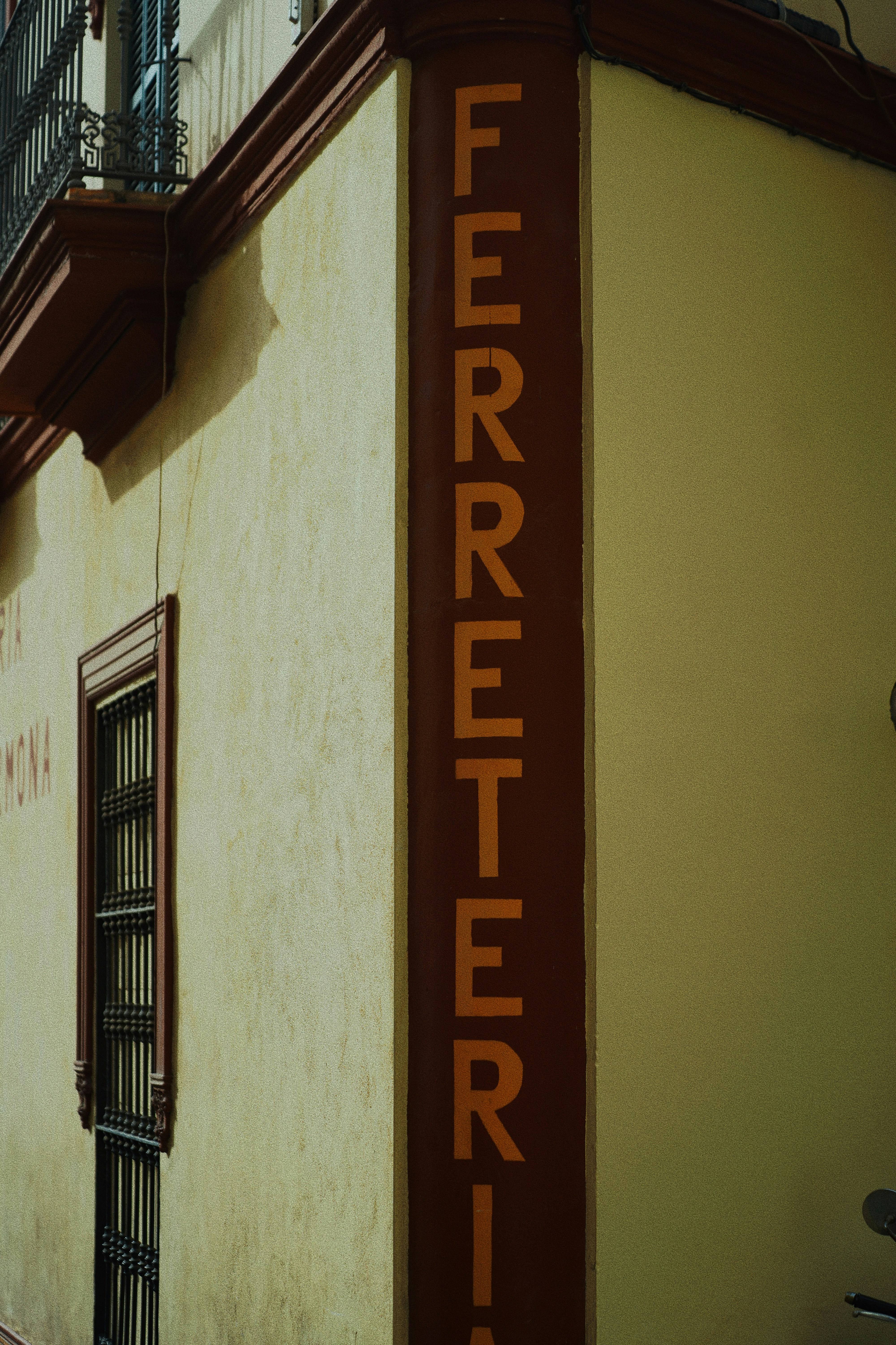 Ferretería Vertical: A Sunlit Corner Sign on a Warm Facade
