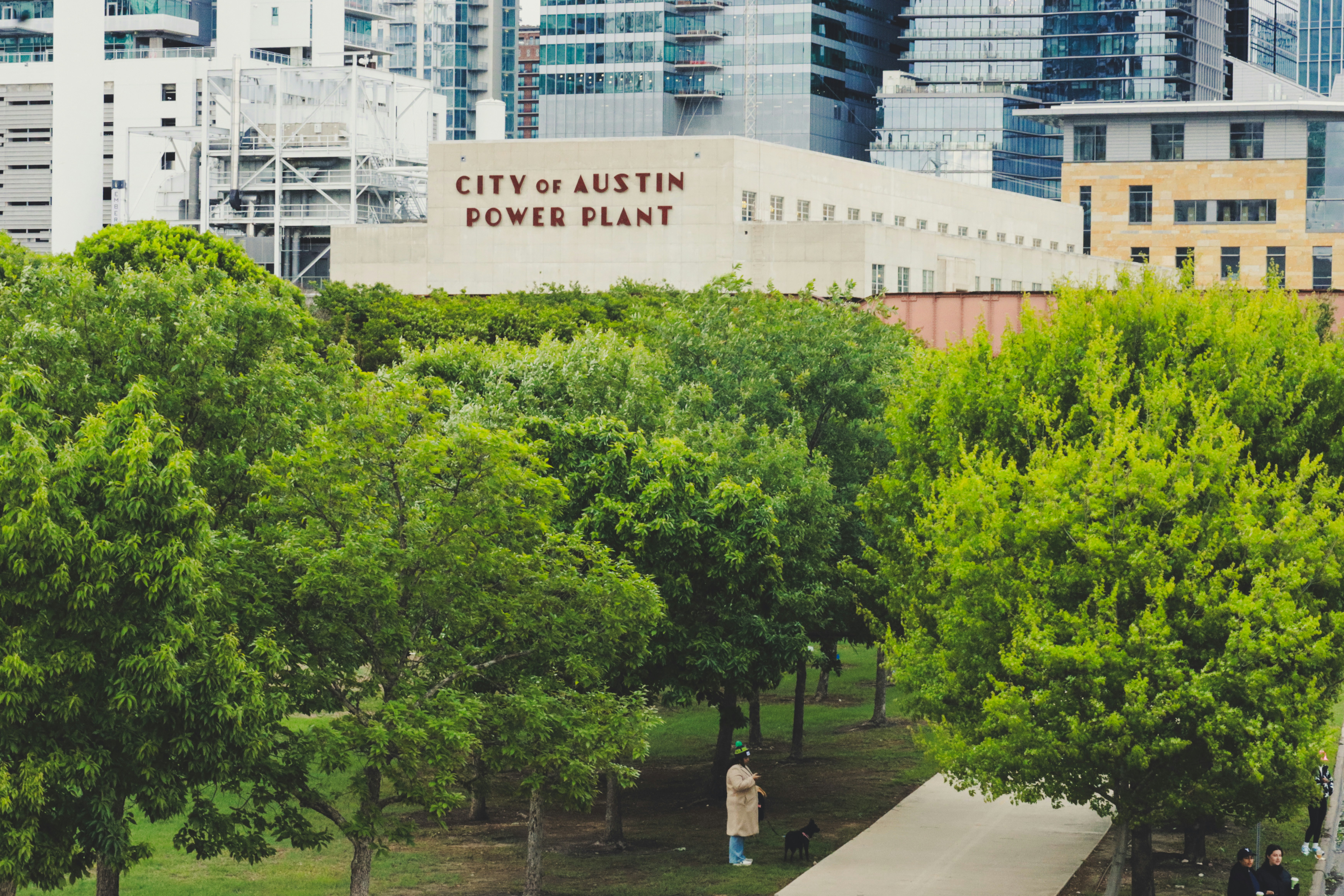 Austin power plant building peeks behind trees. photo – Free City park ...