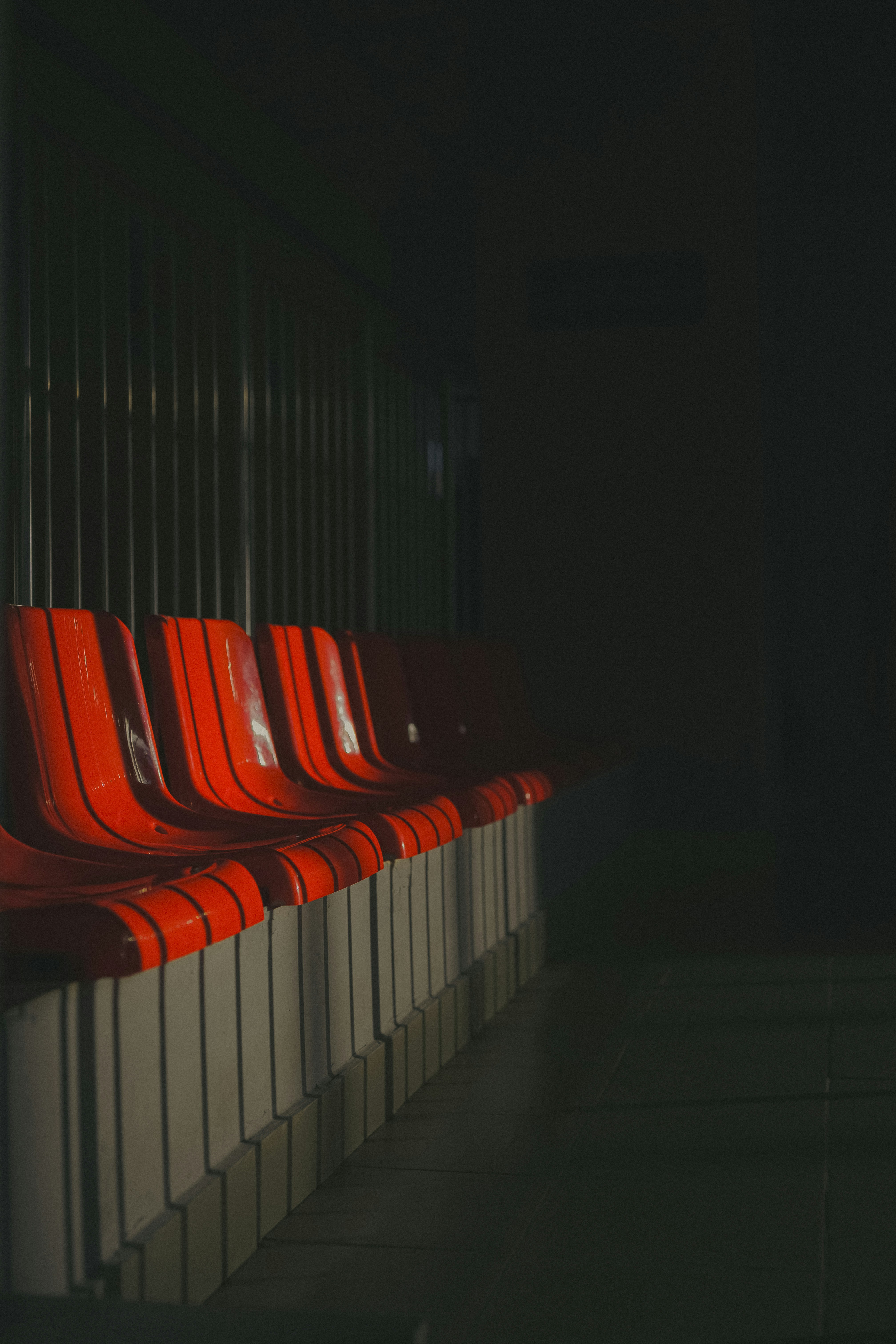Red seats are illuminated in a dark arena. photo – Free Light Image on ...