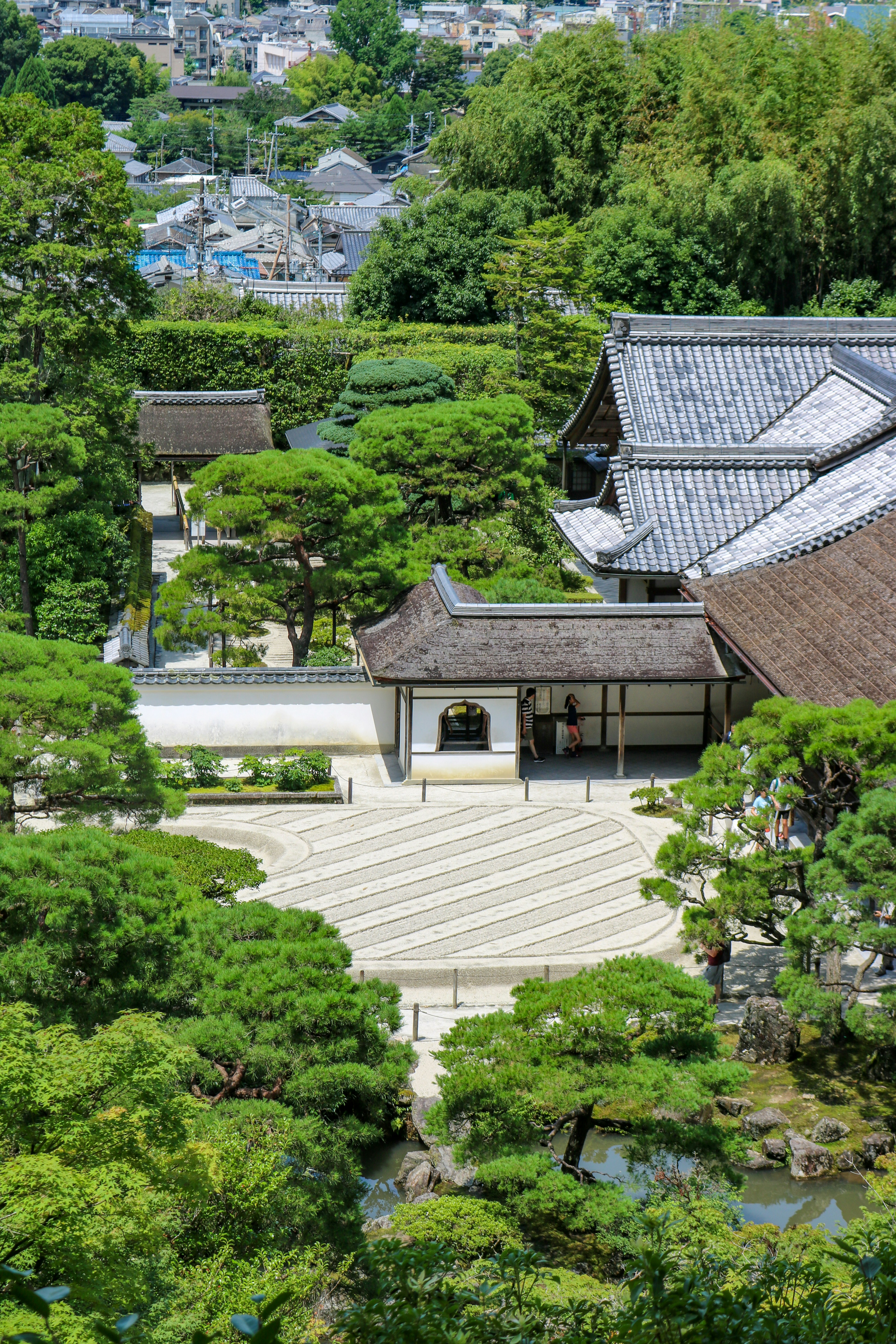 Lush green gardens surround a traditional Japanese building, showcasing meticulous landscaping and serene pathways.
