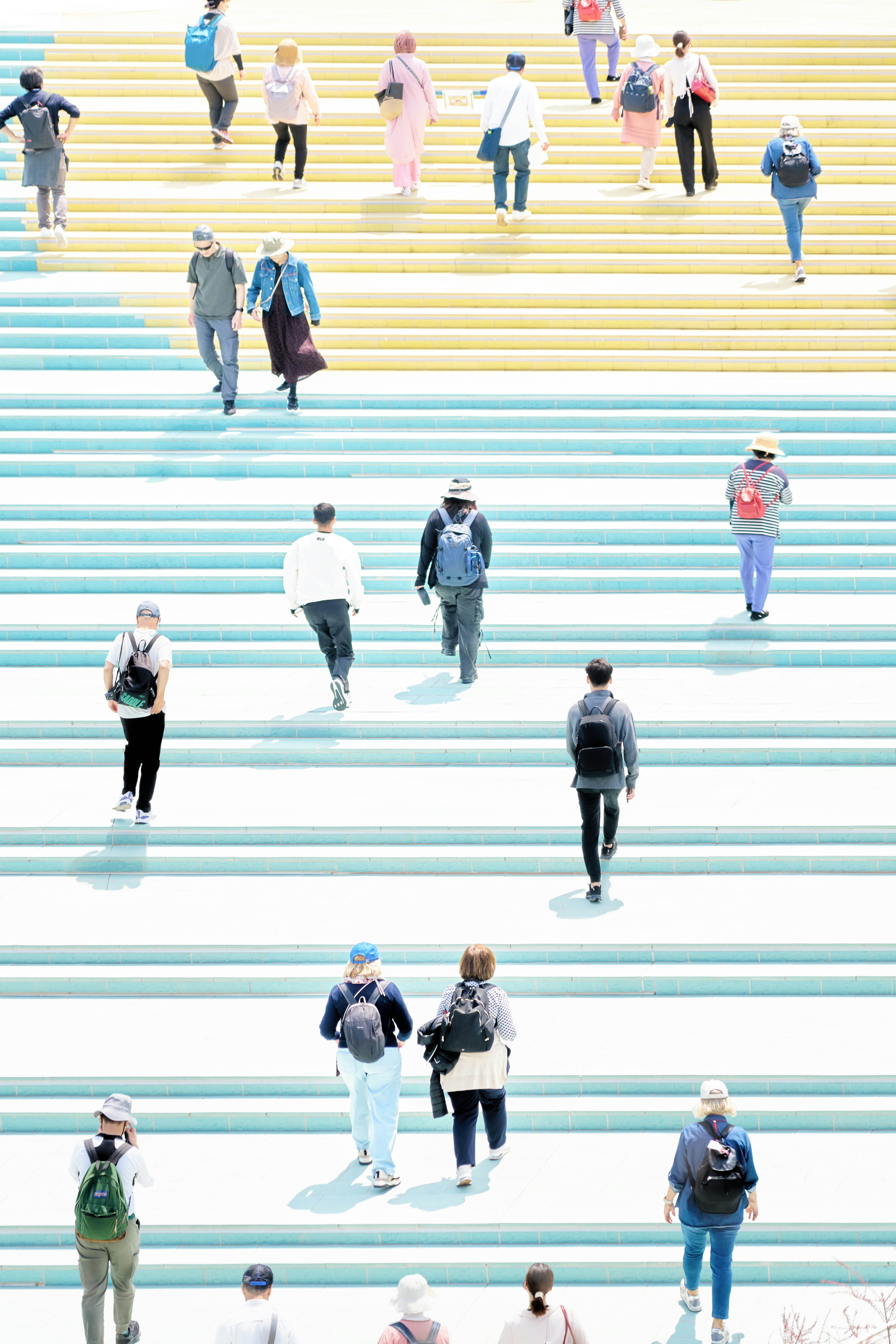 People climb and descend a colorful, layered staircase. photo – Free ...