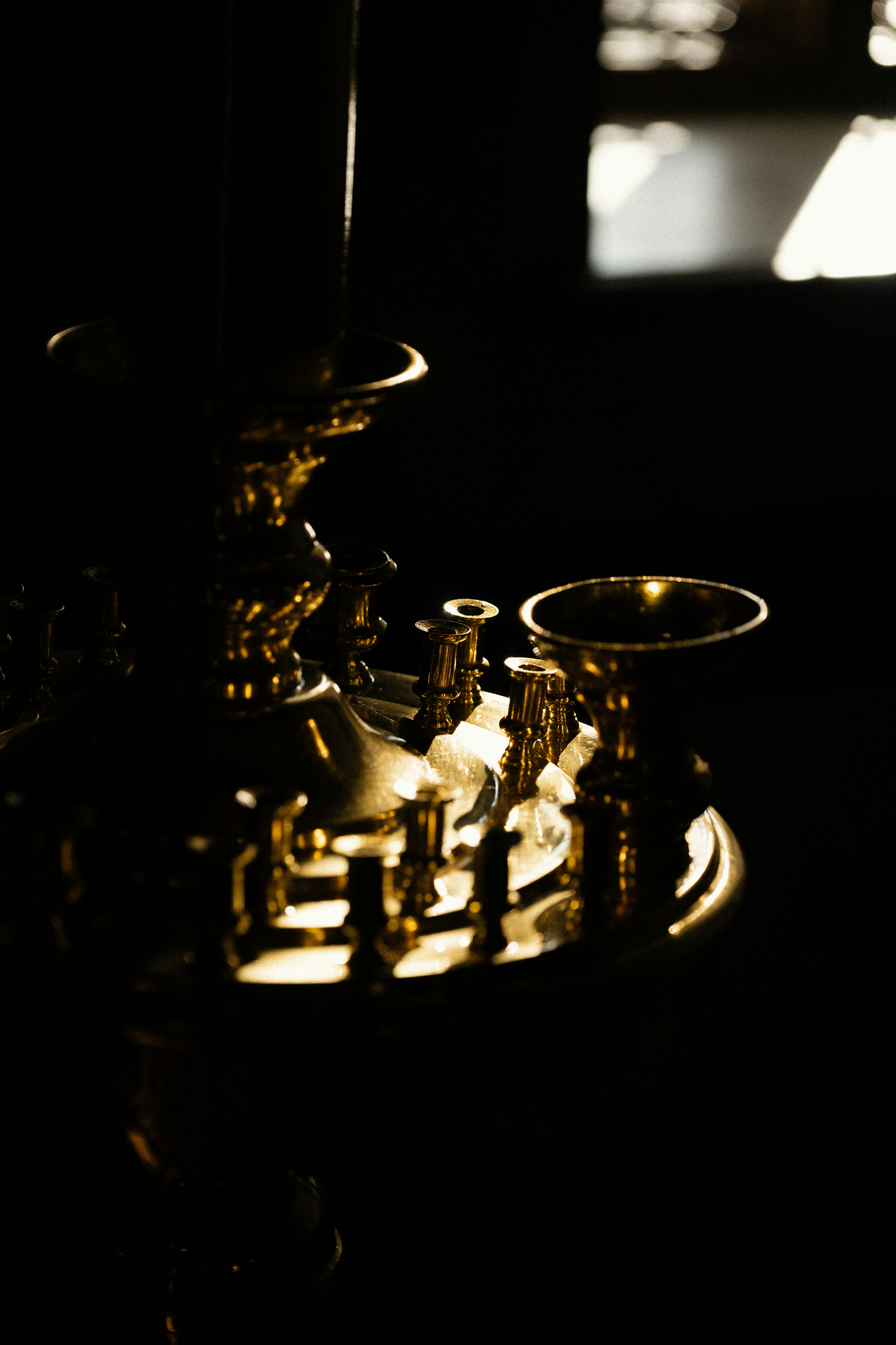 Intricately designed brass candelabra illuminated by soft light, casting delicate shadows in a dimly lit room.