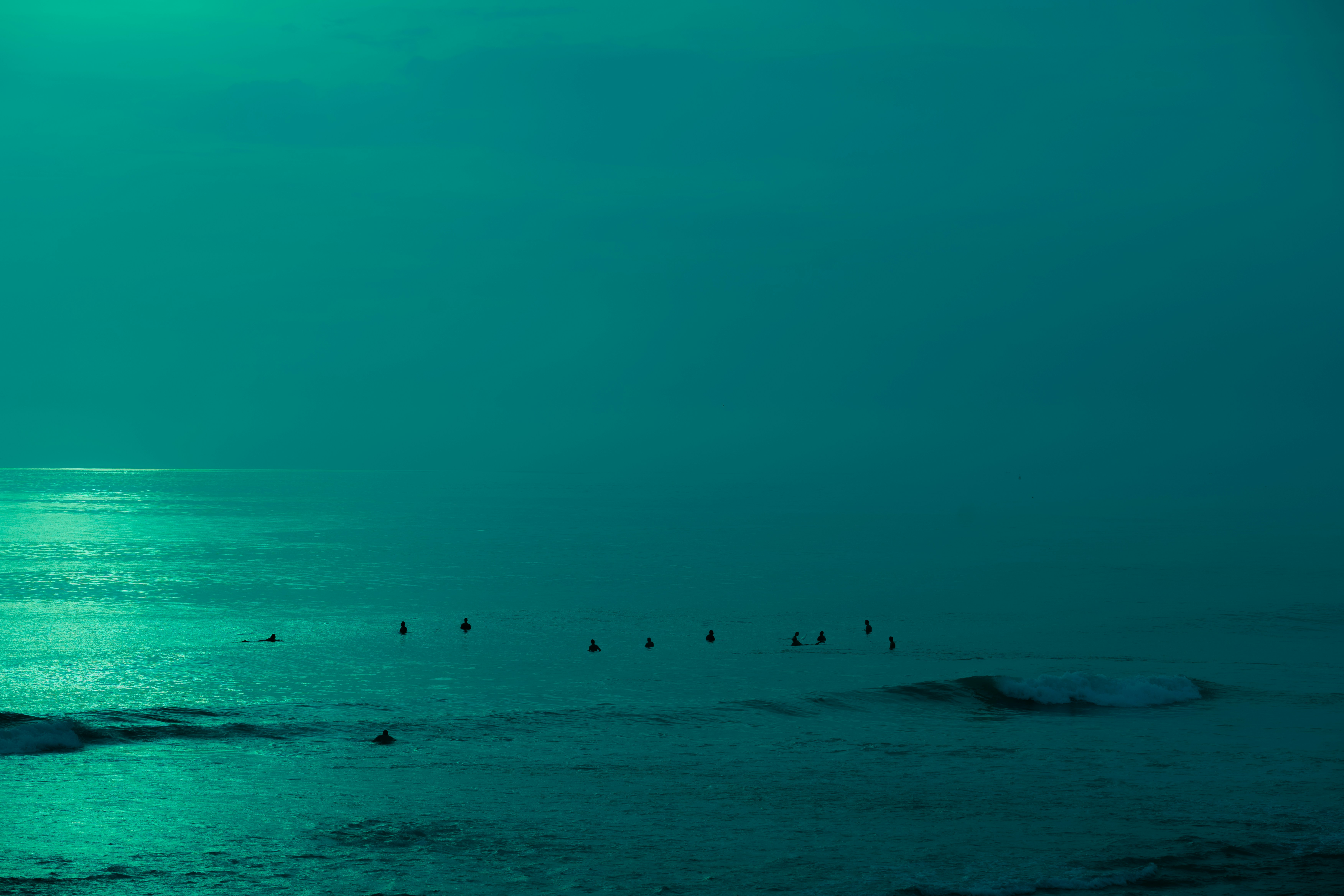 Sunlit Sea: Distant Surfers in a Turquoise Horizon